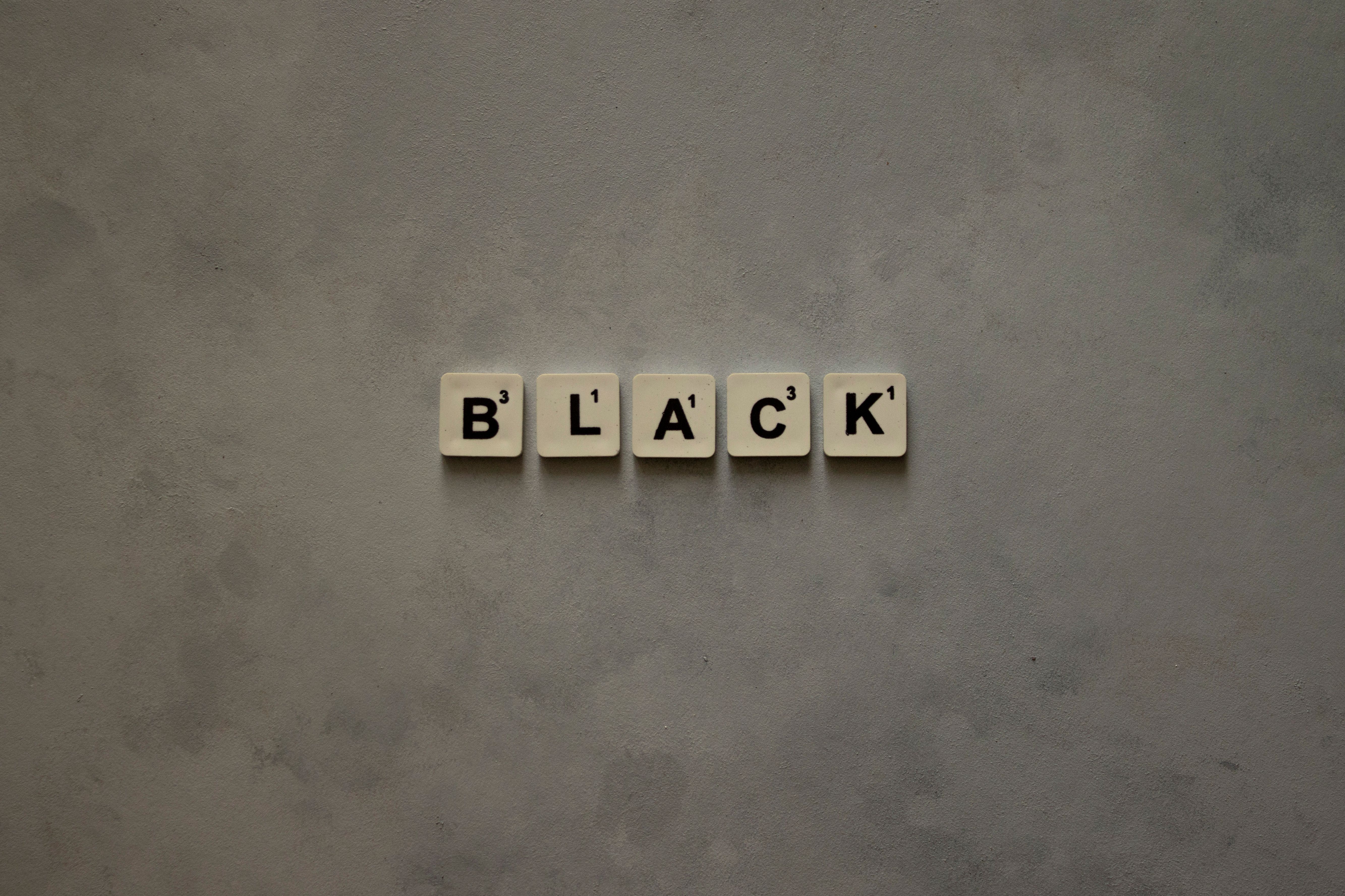 Scrabble Tiles Spelling 'BLACK' on Grey Background · Free Stock Photo