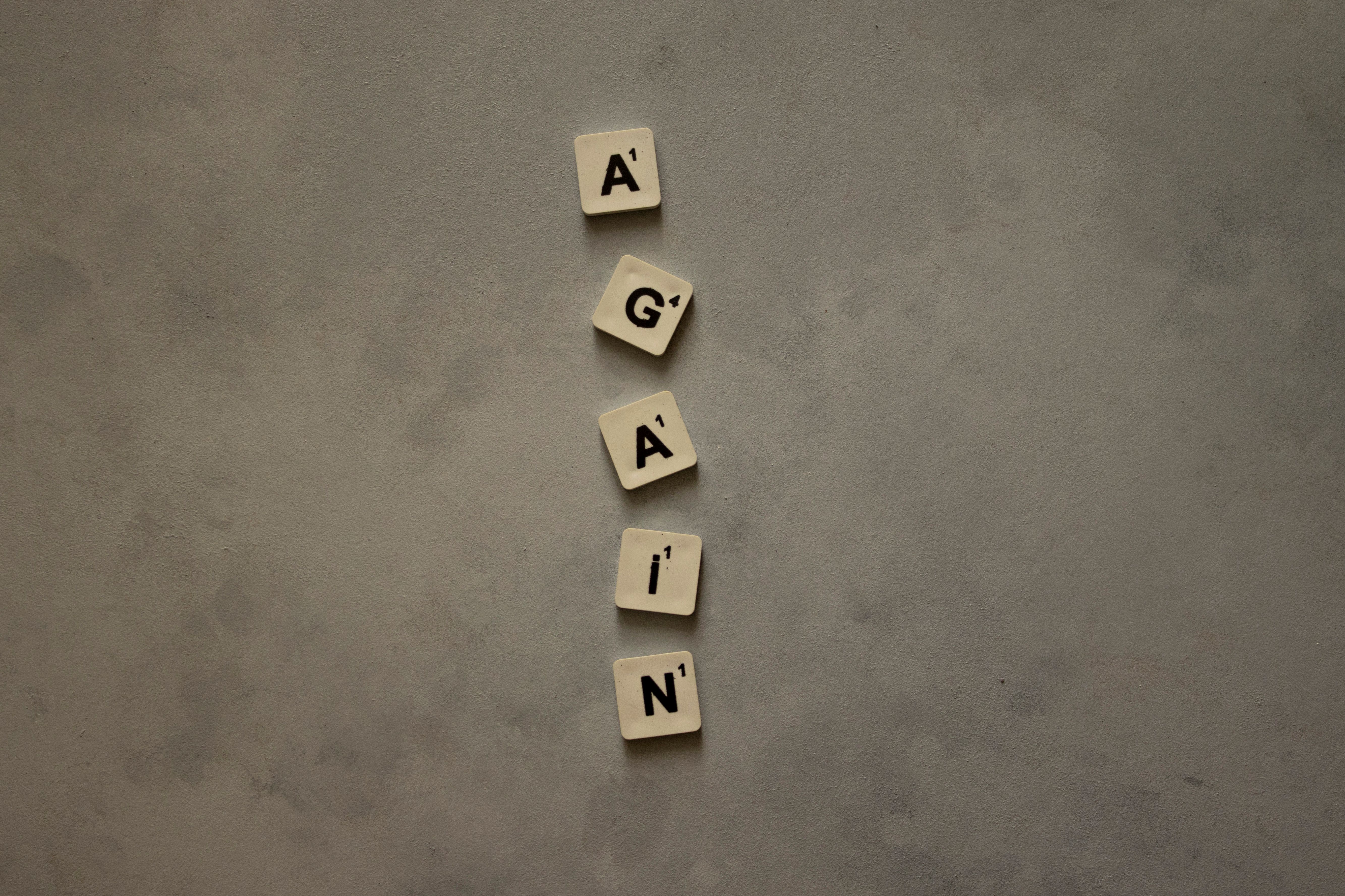Scrabble Tiles Spelling 'Again' on Concrete Background · Free Stock Photo