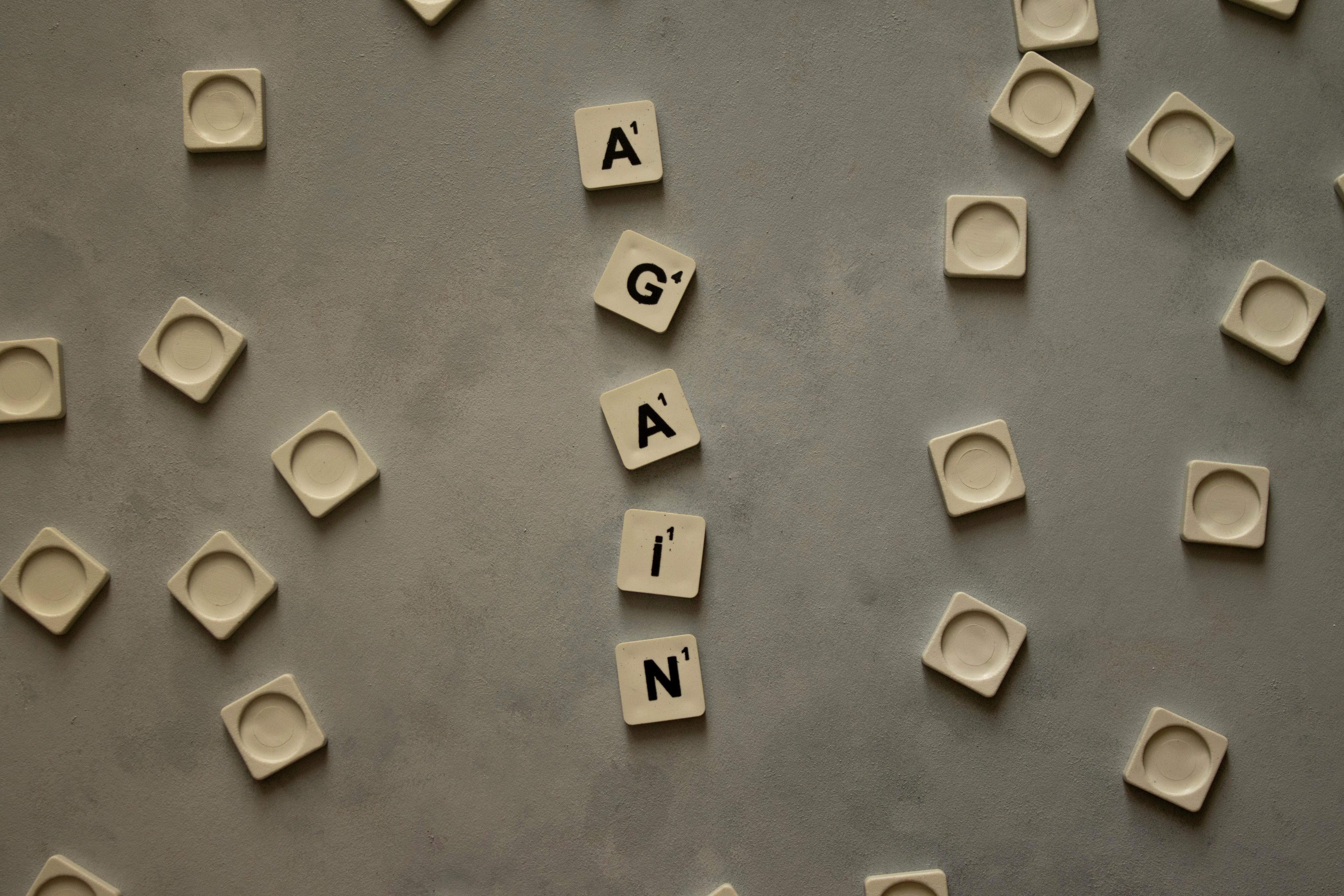 Alphabet Tiles Spelling the Word 'Again' on Gray Surface · Free Stock Photo