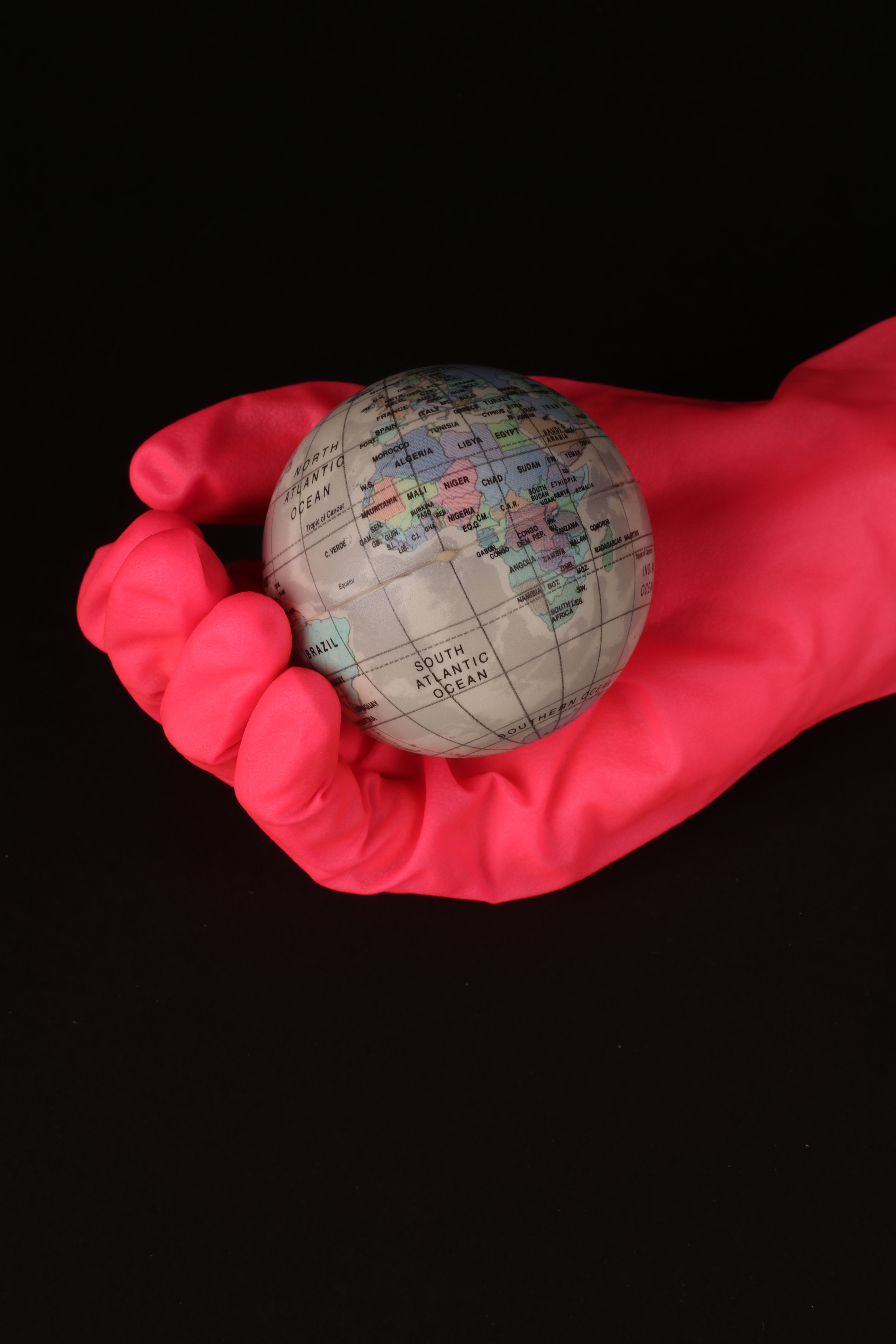 Red Gloved Hand Holding a Small Globe · Free Stock Photo