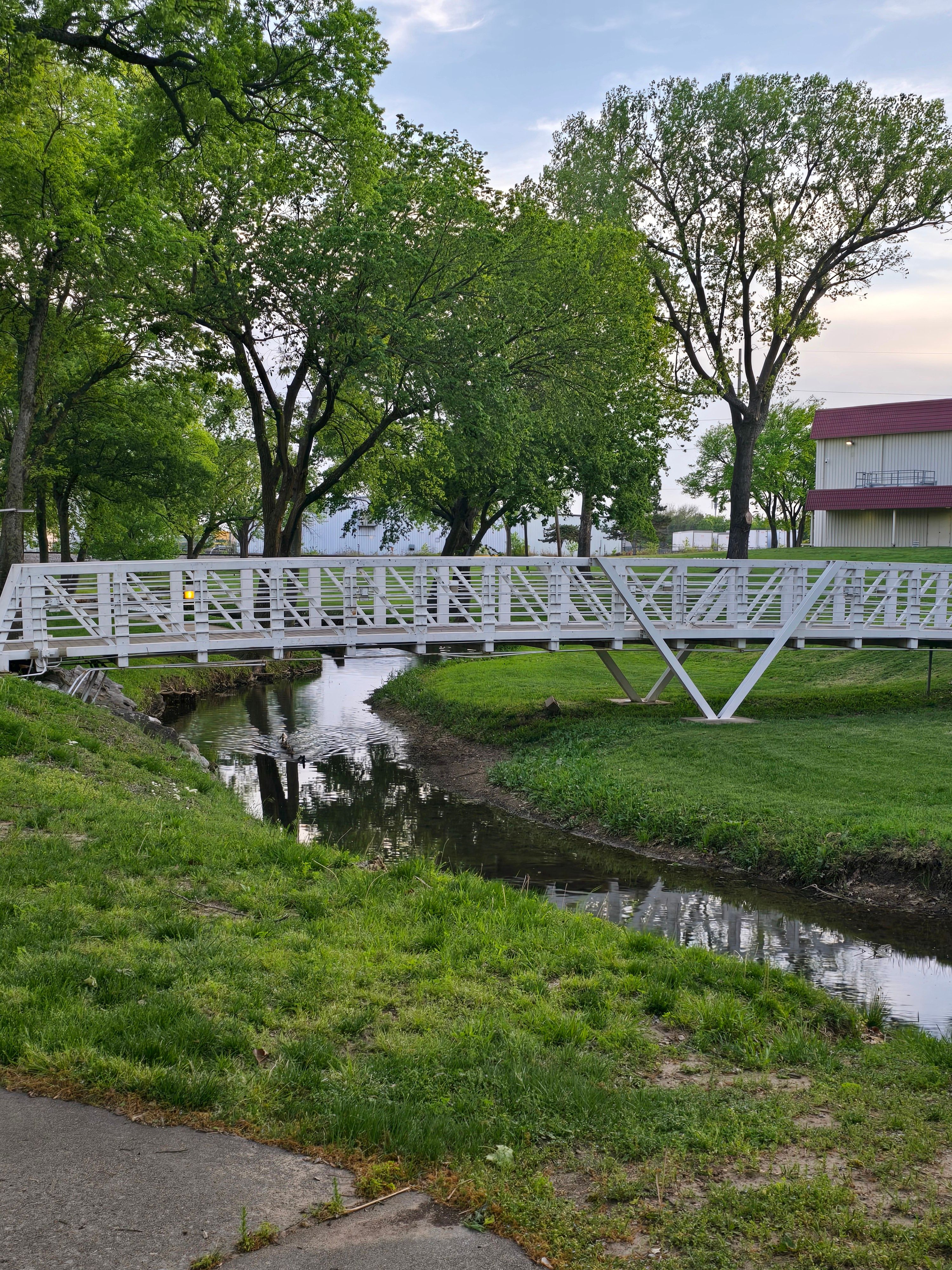 White pedestrian bridge over a tranquil creek · Free Stock Photo