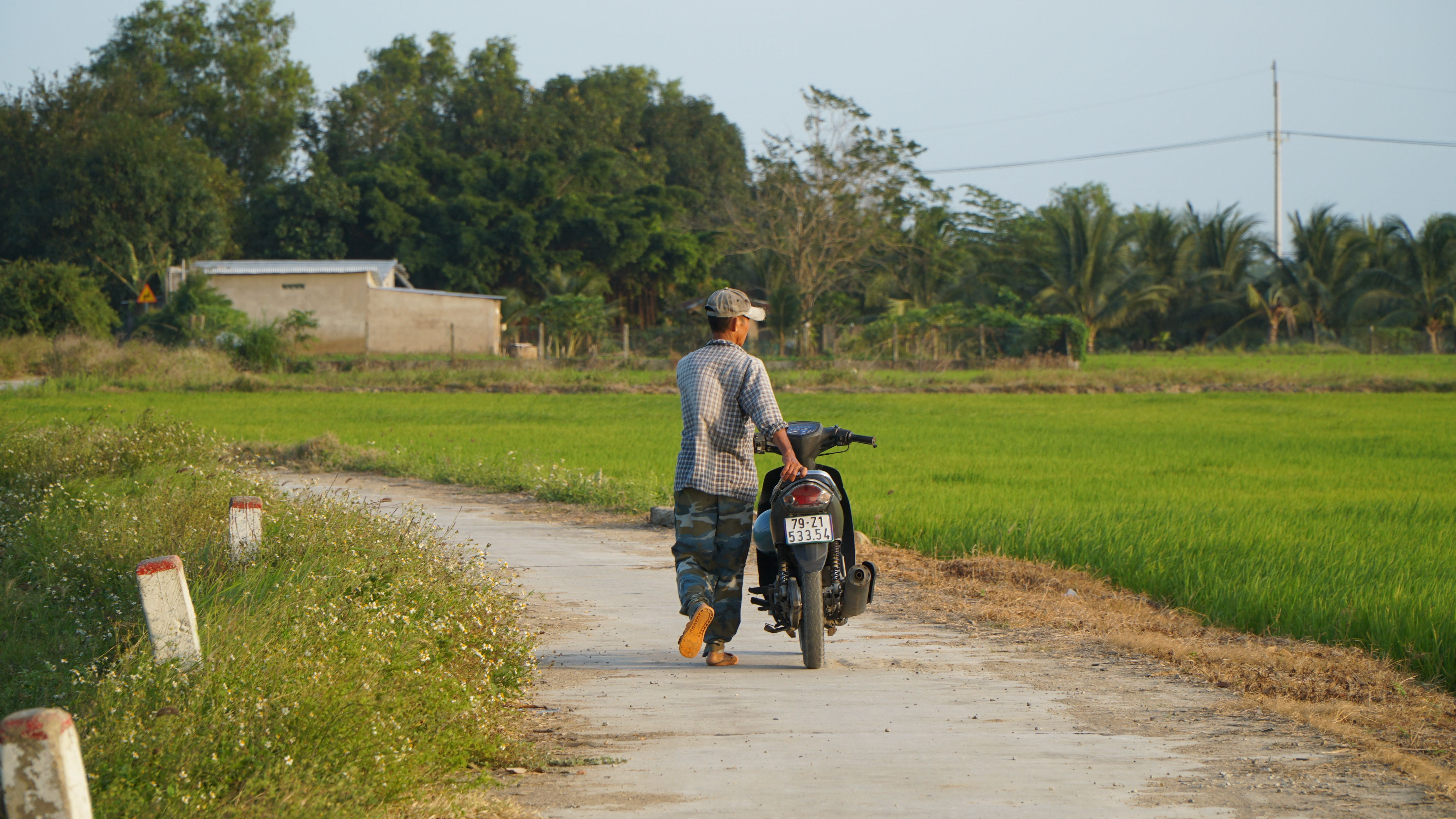 Man Walking Motorcycle on Rural Pathway · Free Stock Photo