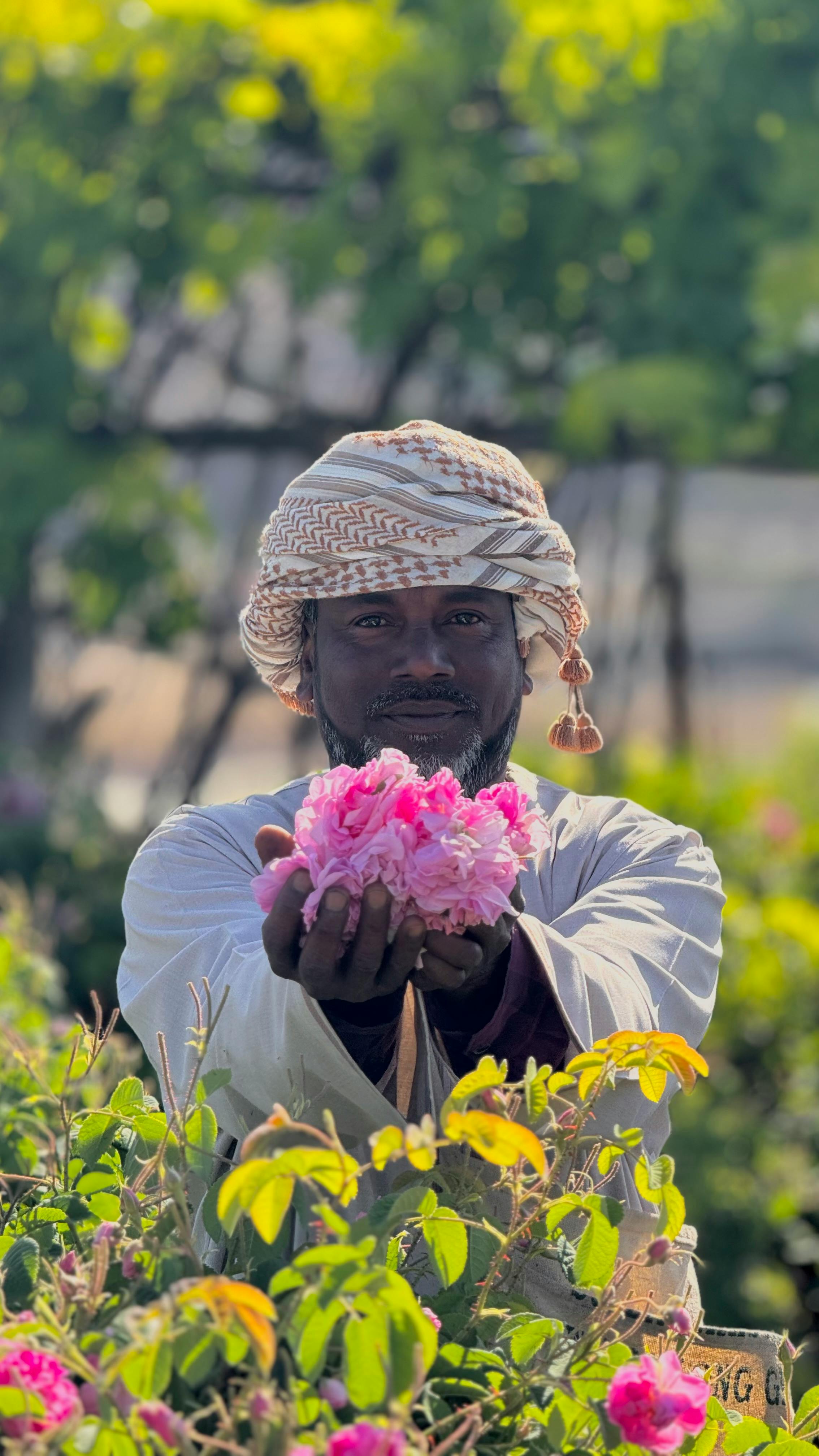 Omani Man Holding Pink Roses in Garden · Free Stock Photo