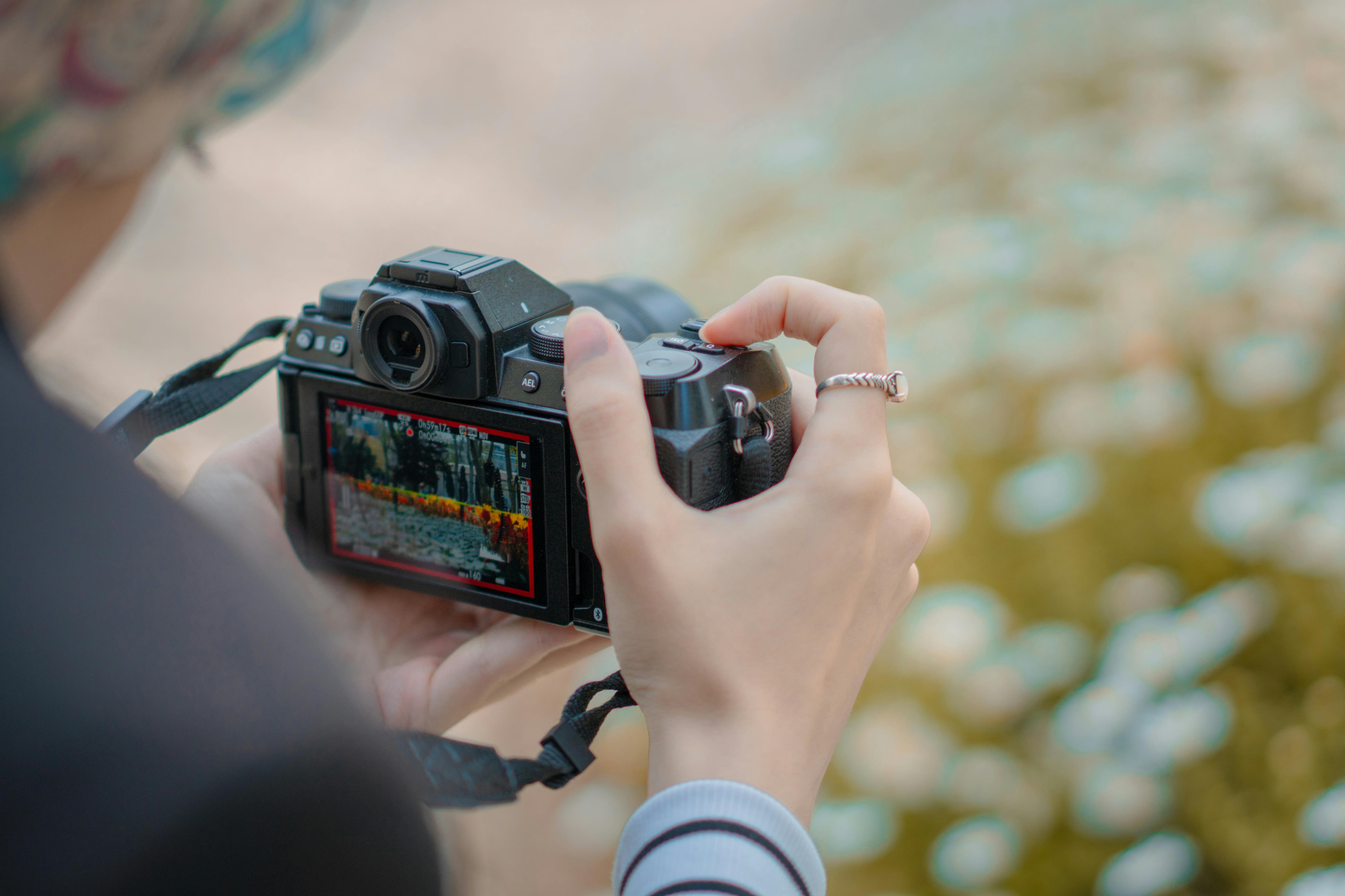 Photographer Adjusting Camera Settings Outdoors · Free Stock Photo