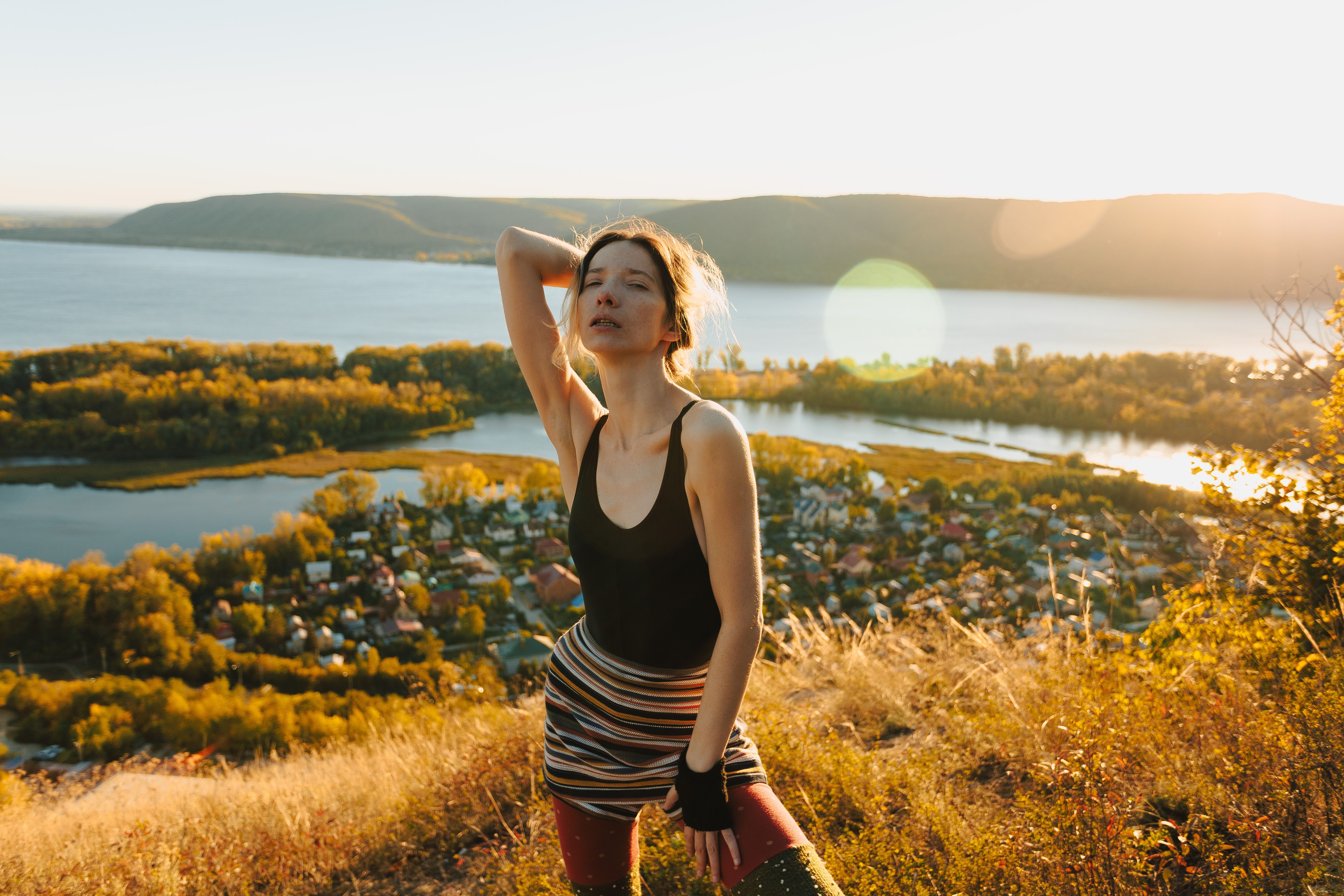 Young Woman Posing on Scenic Hilltop at Sunset · Free Stock Photo
