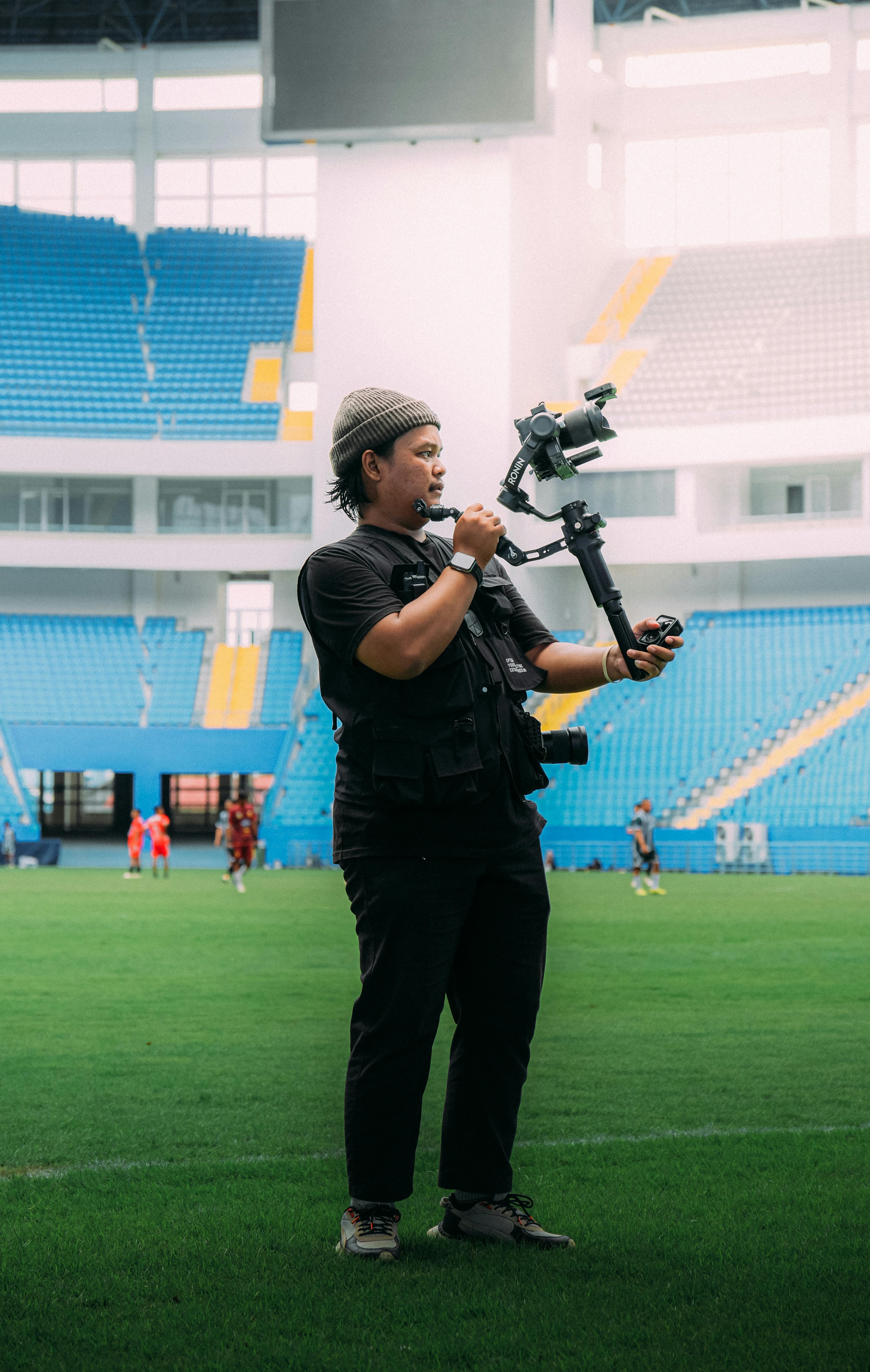 Sports Videographer Operating Camera in Stadium · Free Stock Photo