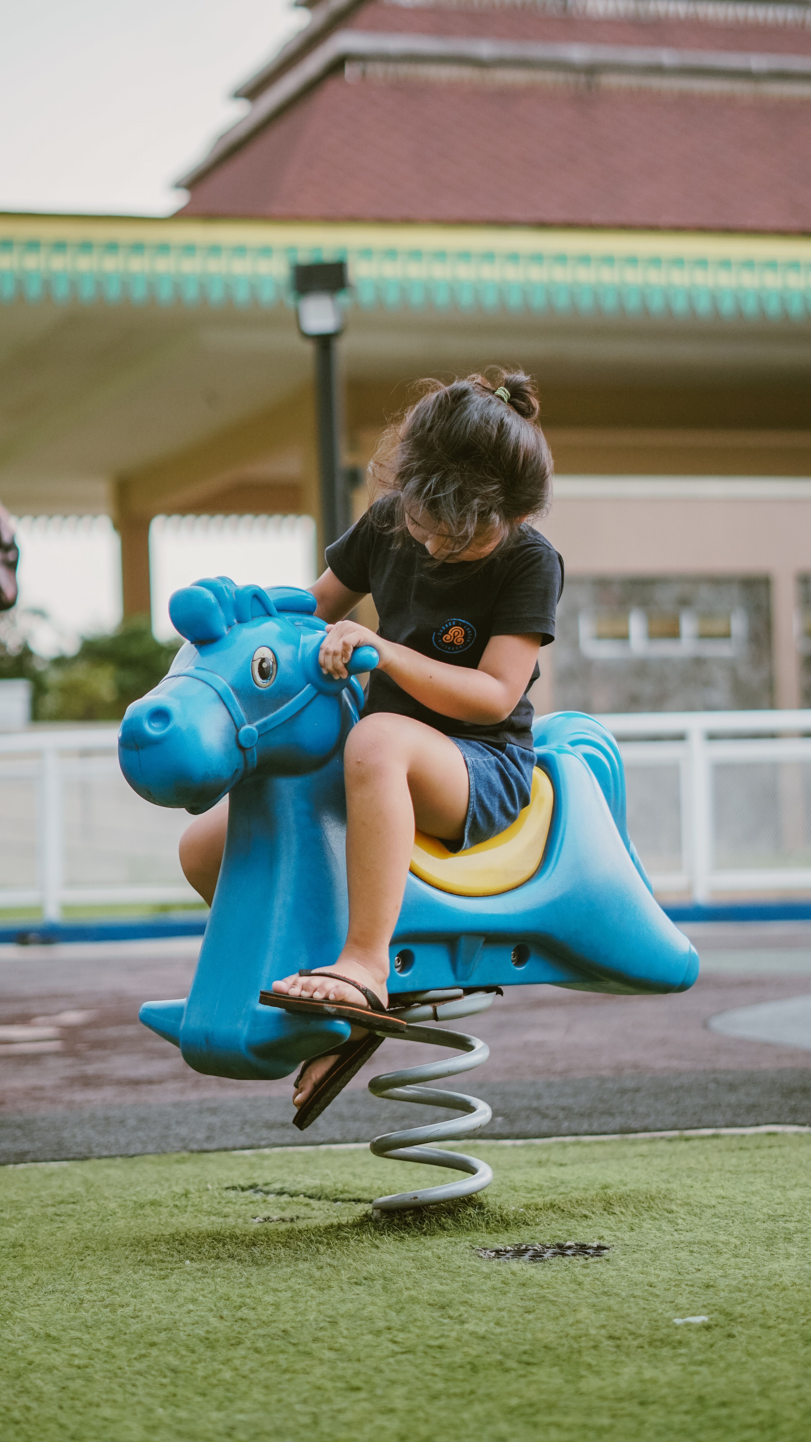 Child Enjoying Playtime on Vibrant Blue Spring Ride · Free Stock Photo