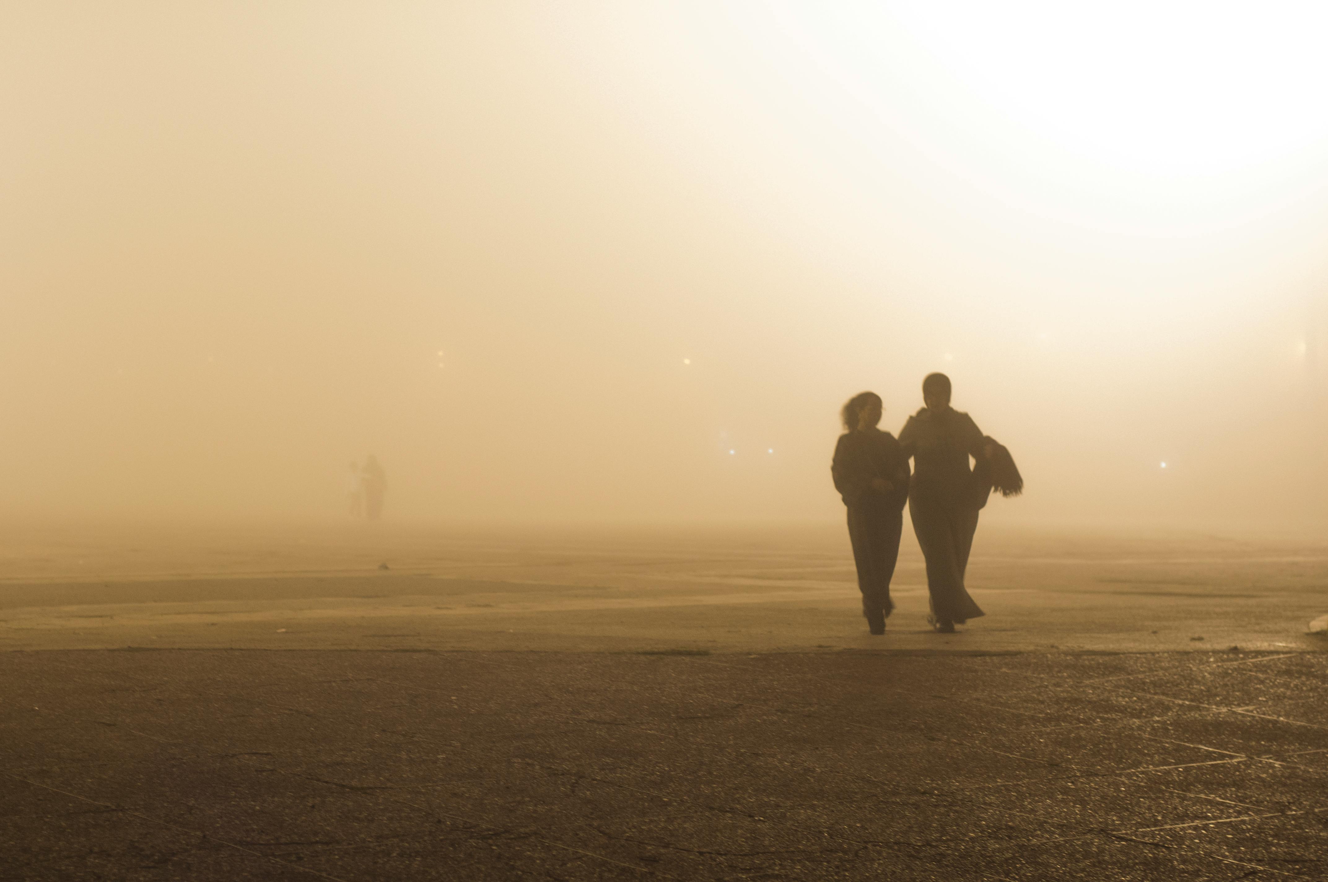 Unrecognizable ethnic women walking in fog · Free Stock Photo