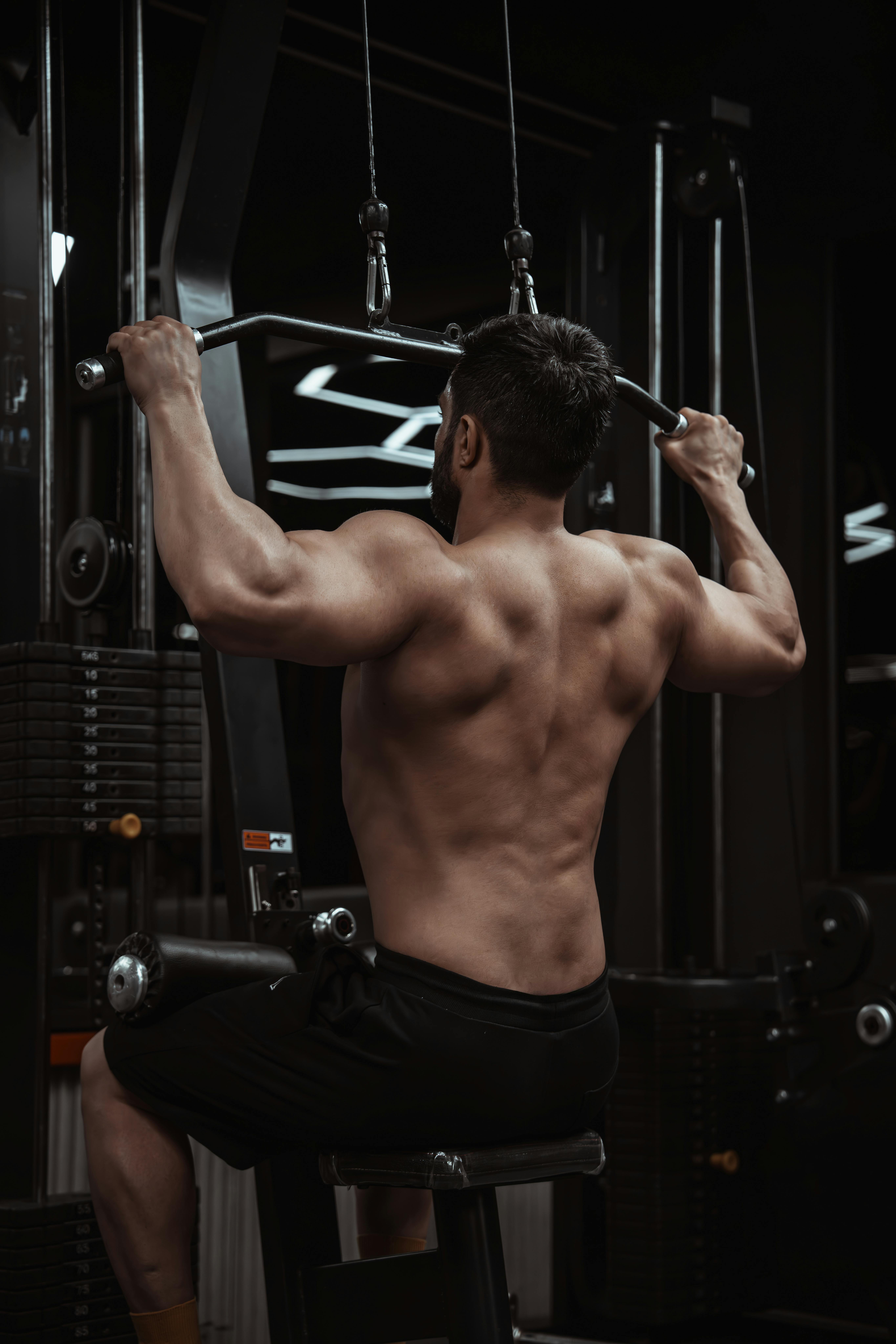 Strong man doing lat pulldown workout in gym · Free Stock Photo