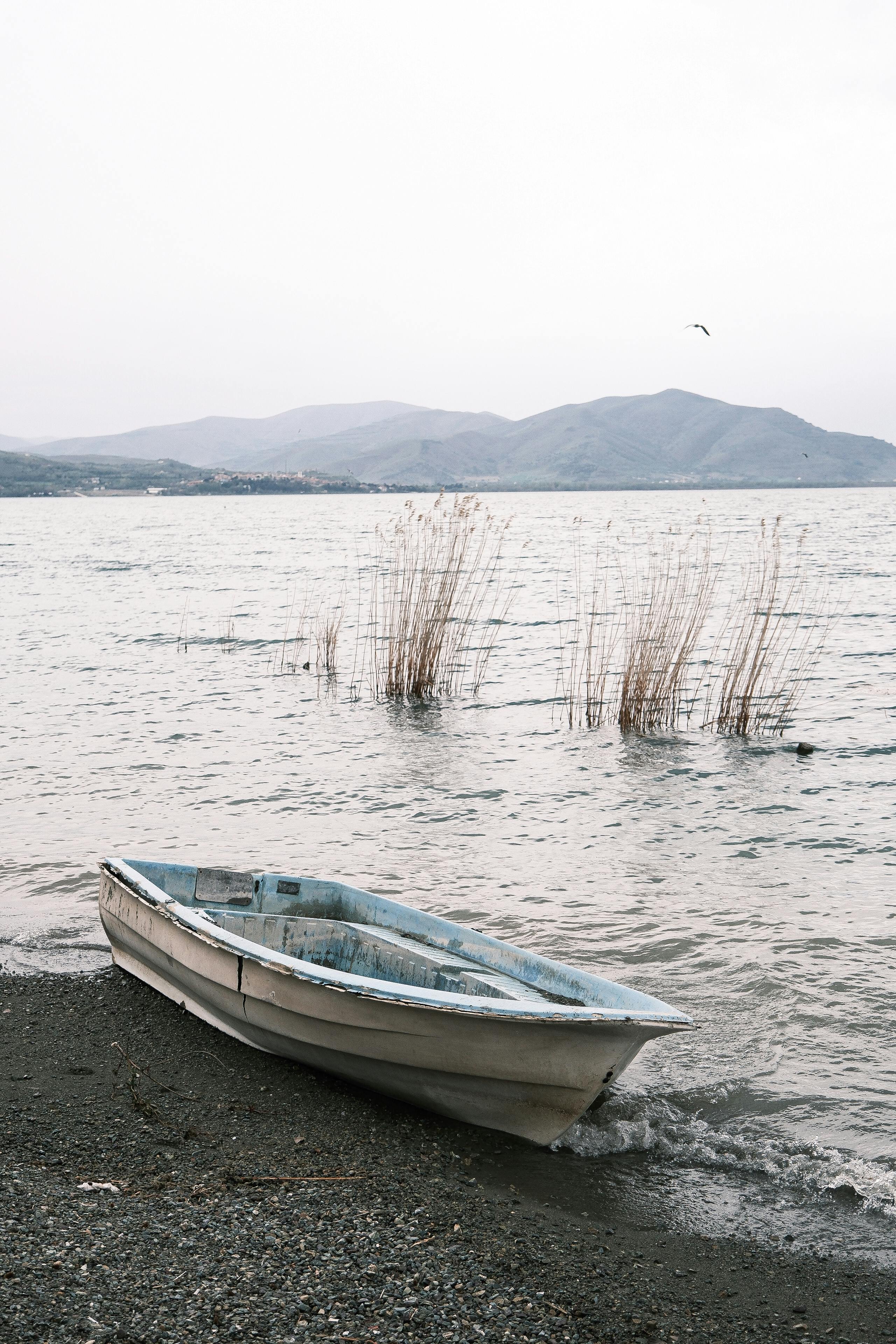 Serene Lakeside Boat with Mountainous Horizon · Free Stock Photo
