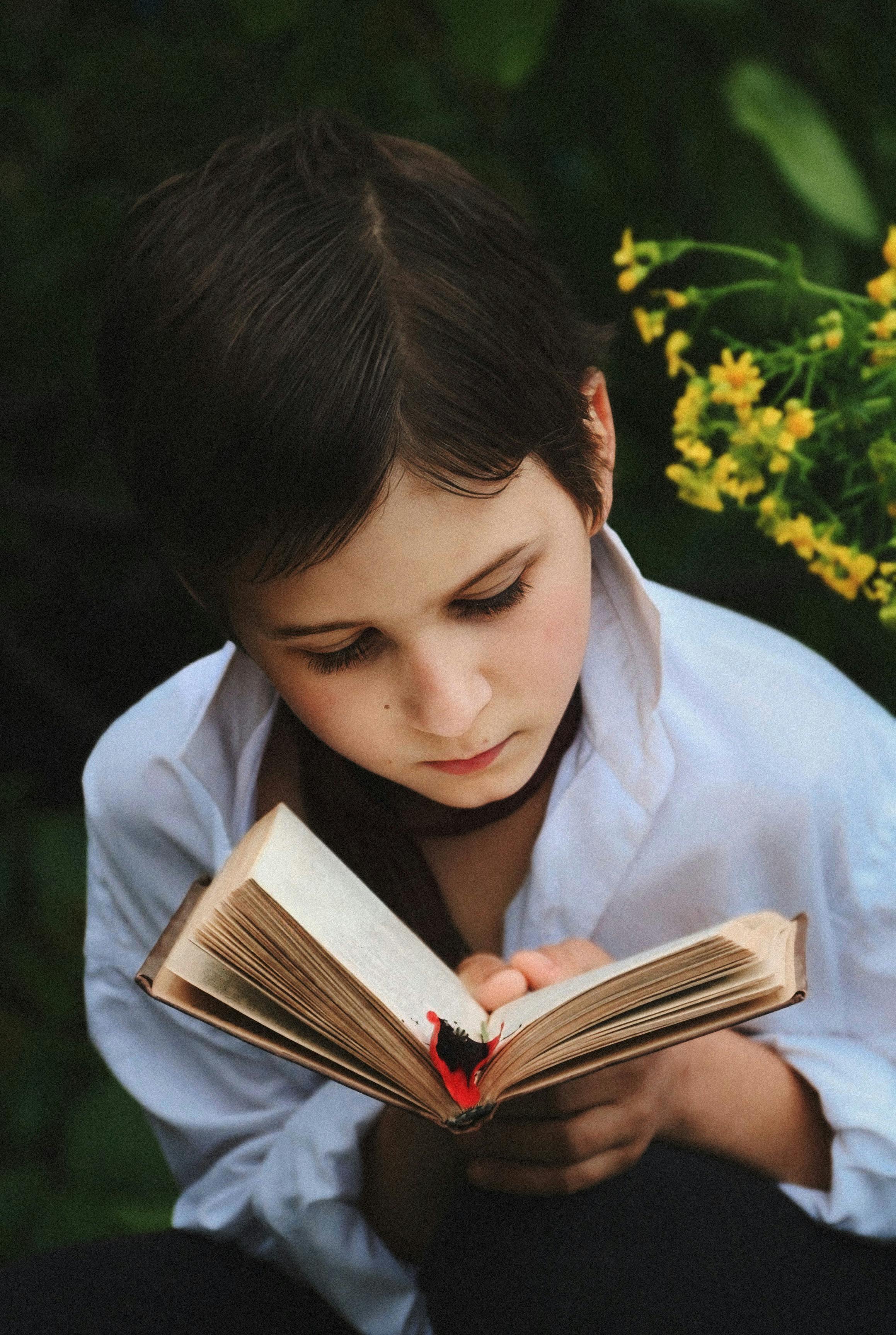 Young Child Reading Book in Garden Setting · Free Stock Photo