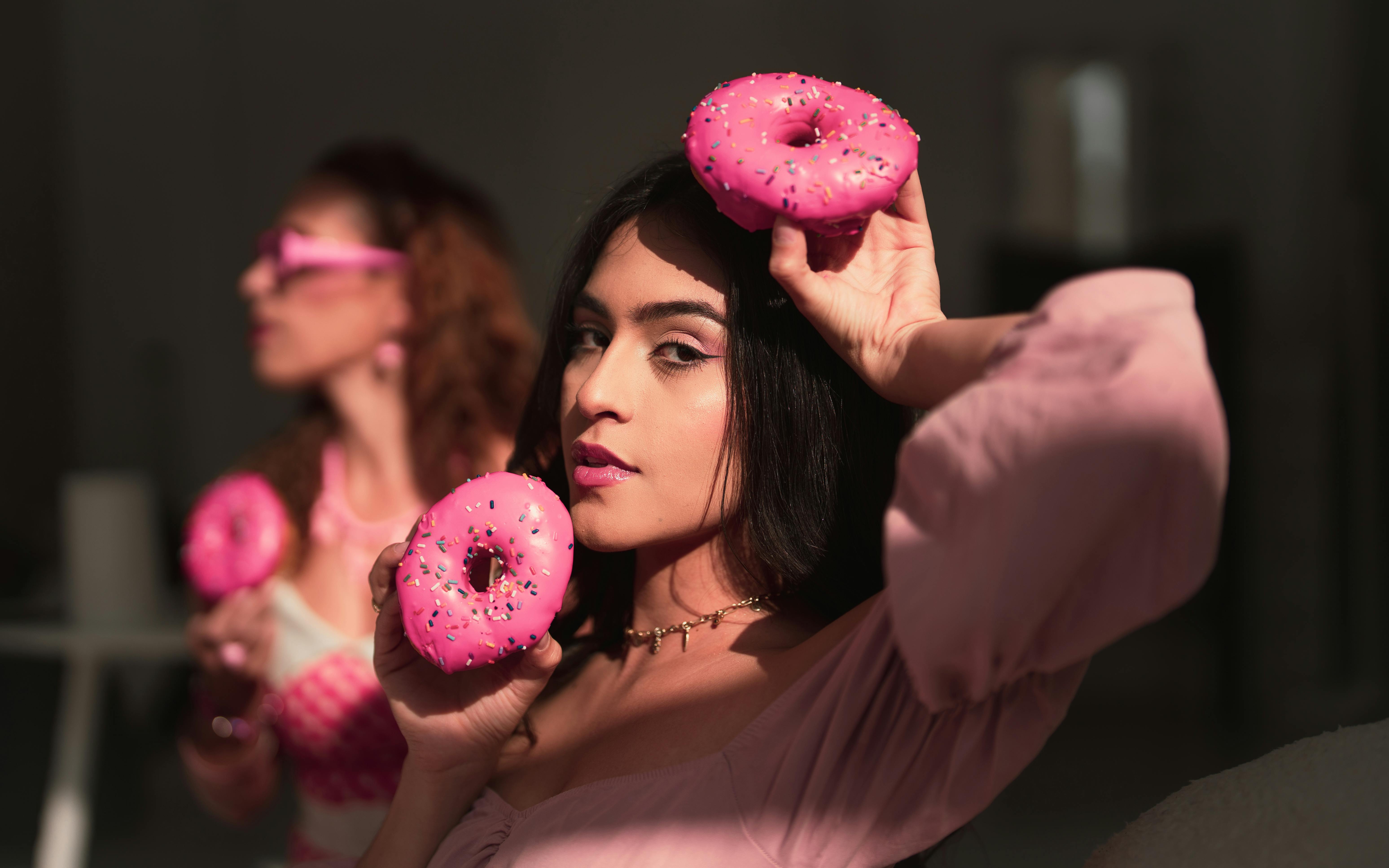 Stylish Women Holding Pink Doughnuts Indoors · Free Stock Photo
