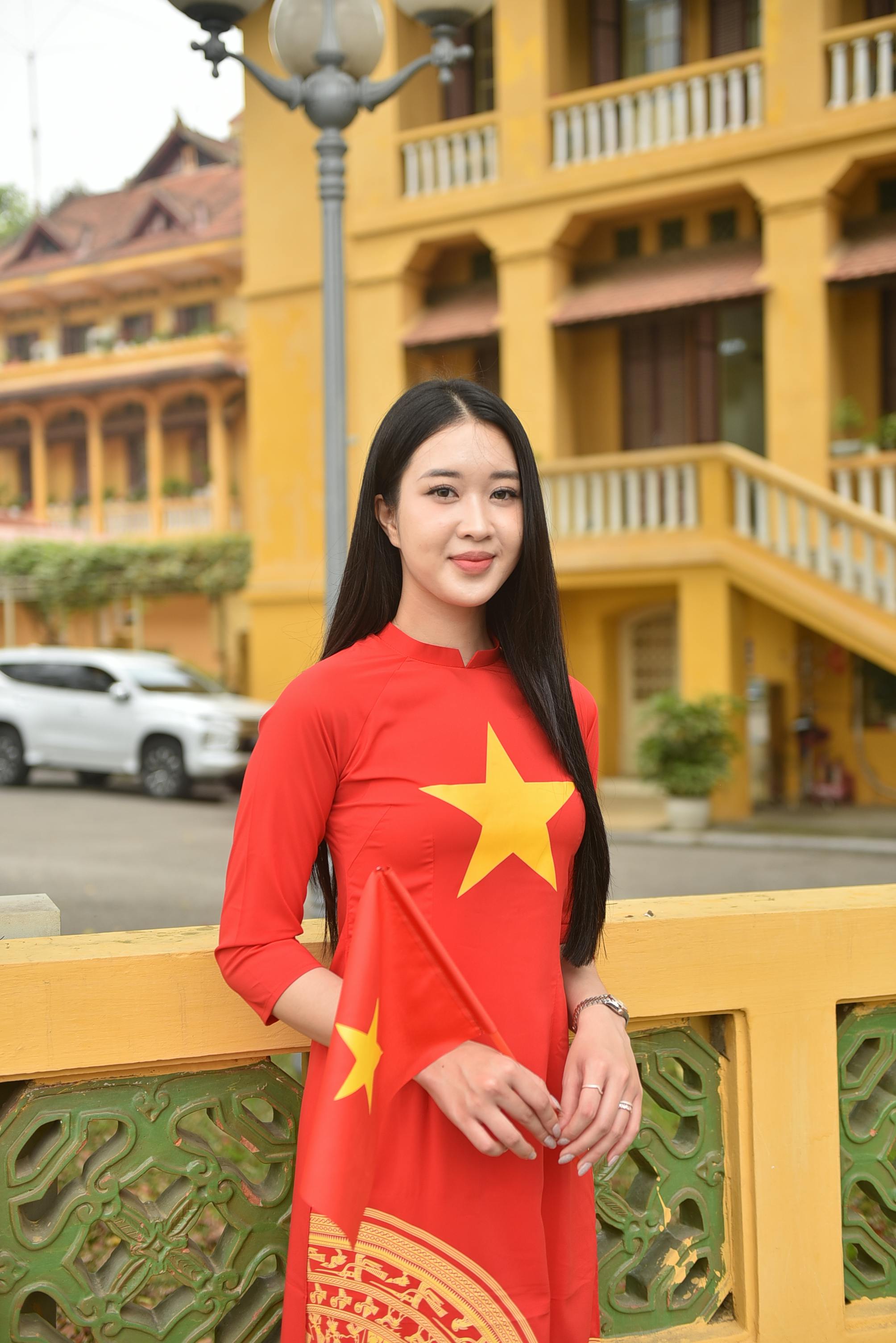 Young Woman in Red Ao Dai Holding Flag Outdoors · Free Stock Photo