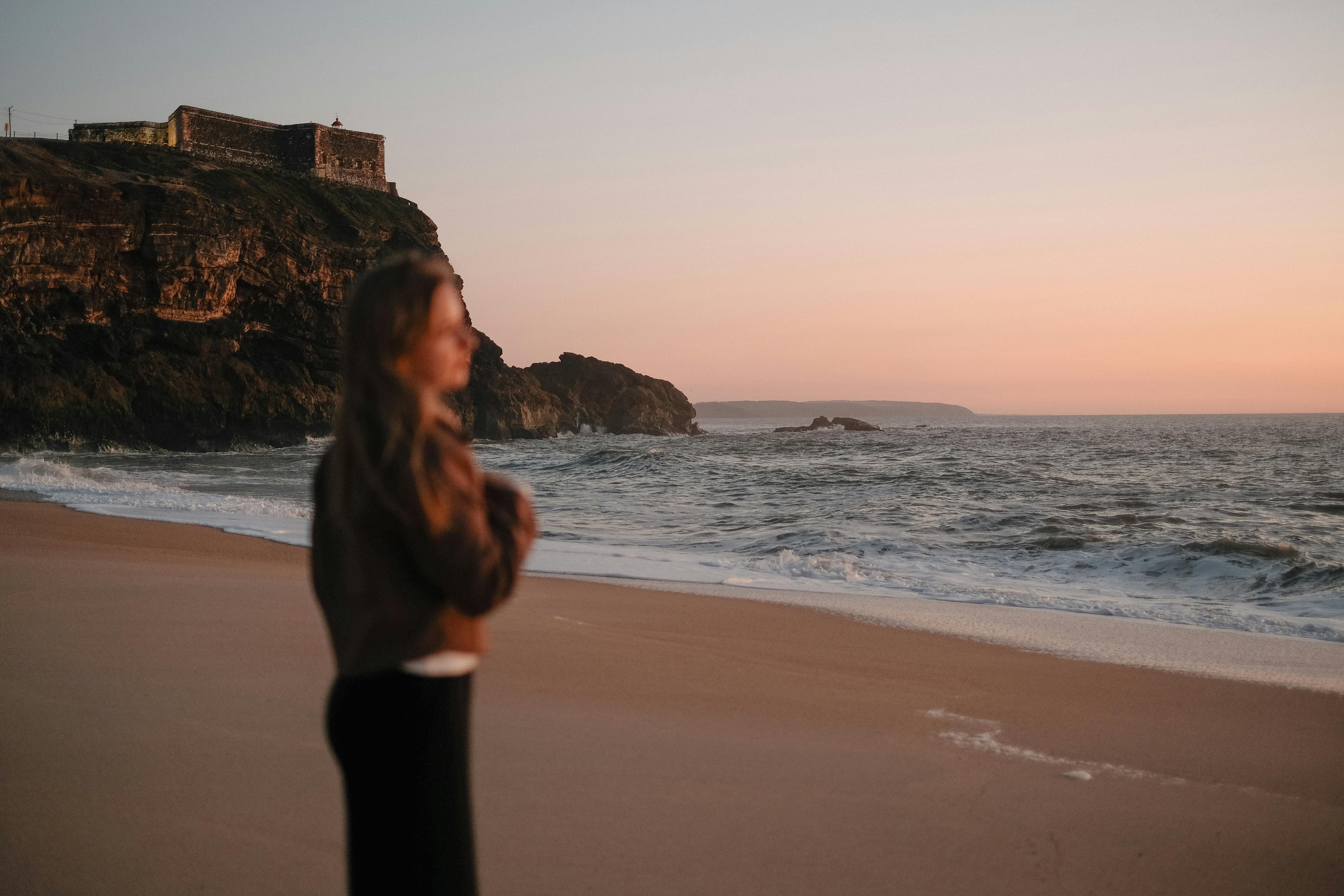 Woman Contemplates Sunset on Nazare Beach · Free Stock Photo