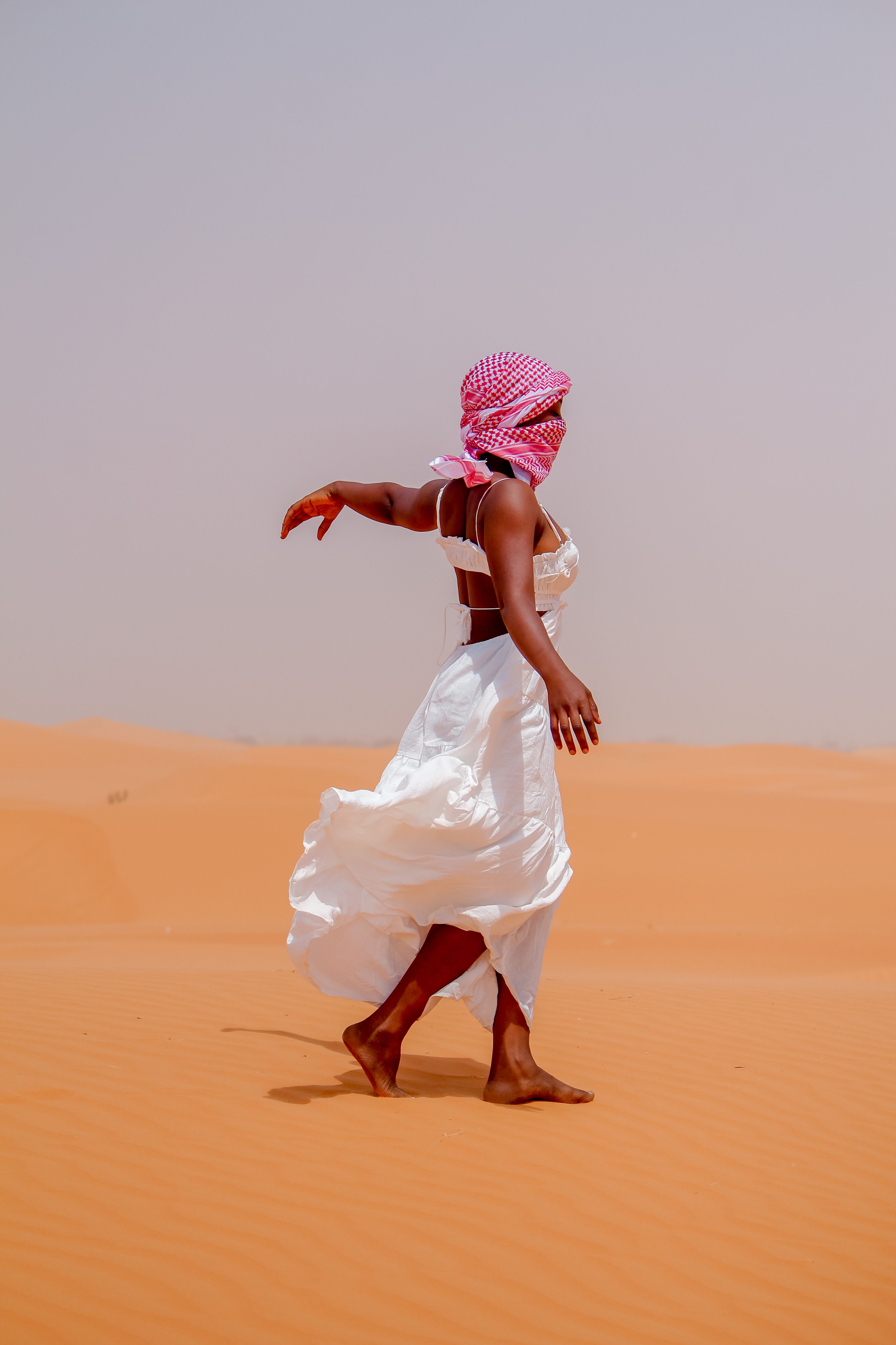 Jumping Figure in Desert Wearing Traditional Scarf · Free Stock Photo