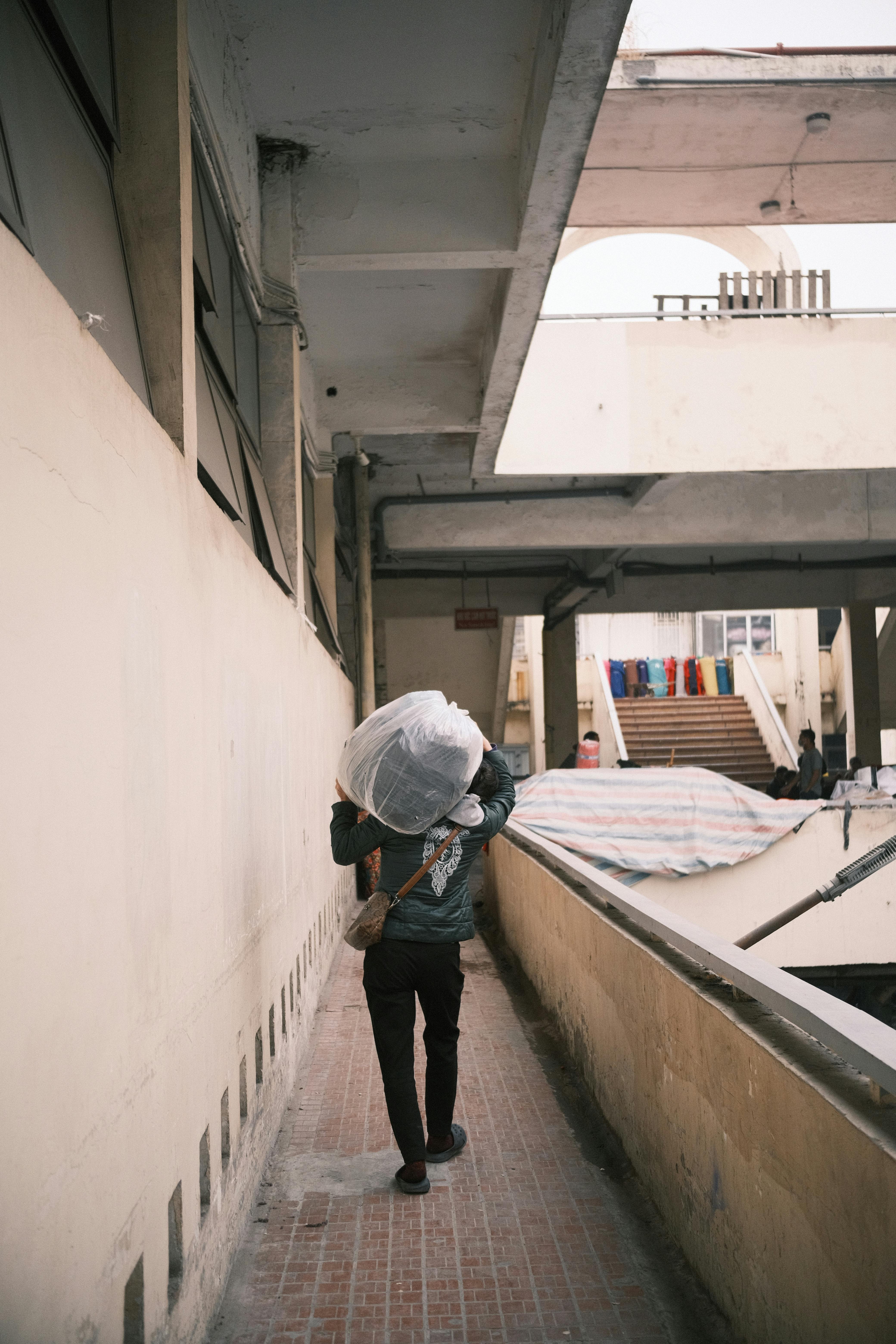 Man Carrying Large Bag in Urban Alleyway · Free Stock Photo