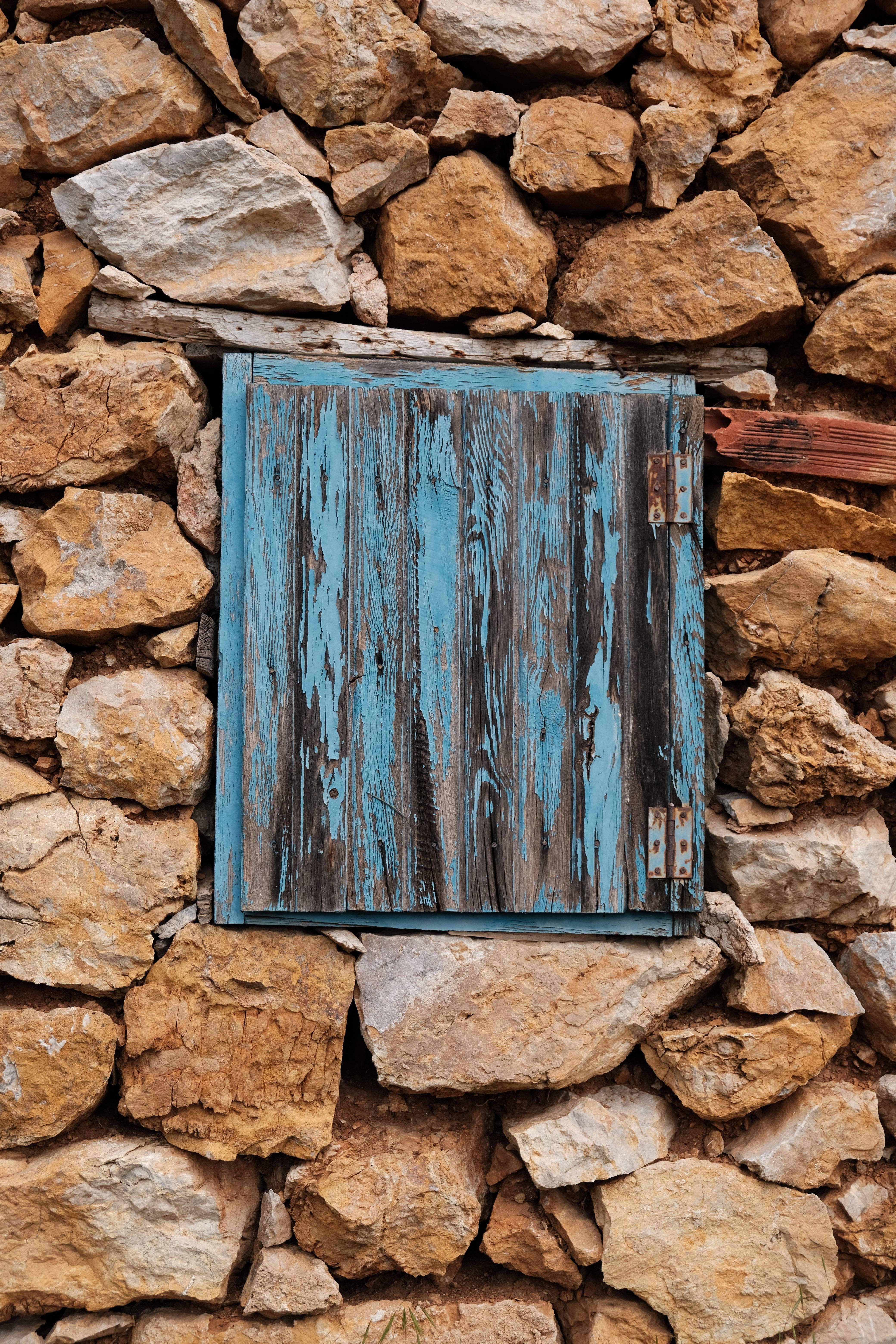 Rustic Stone Wall with Weathered Blue Shutter · Free Stock Photo