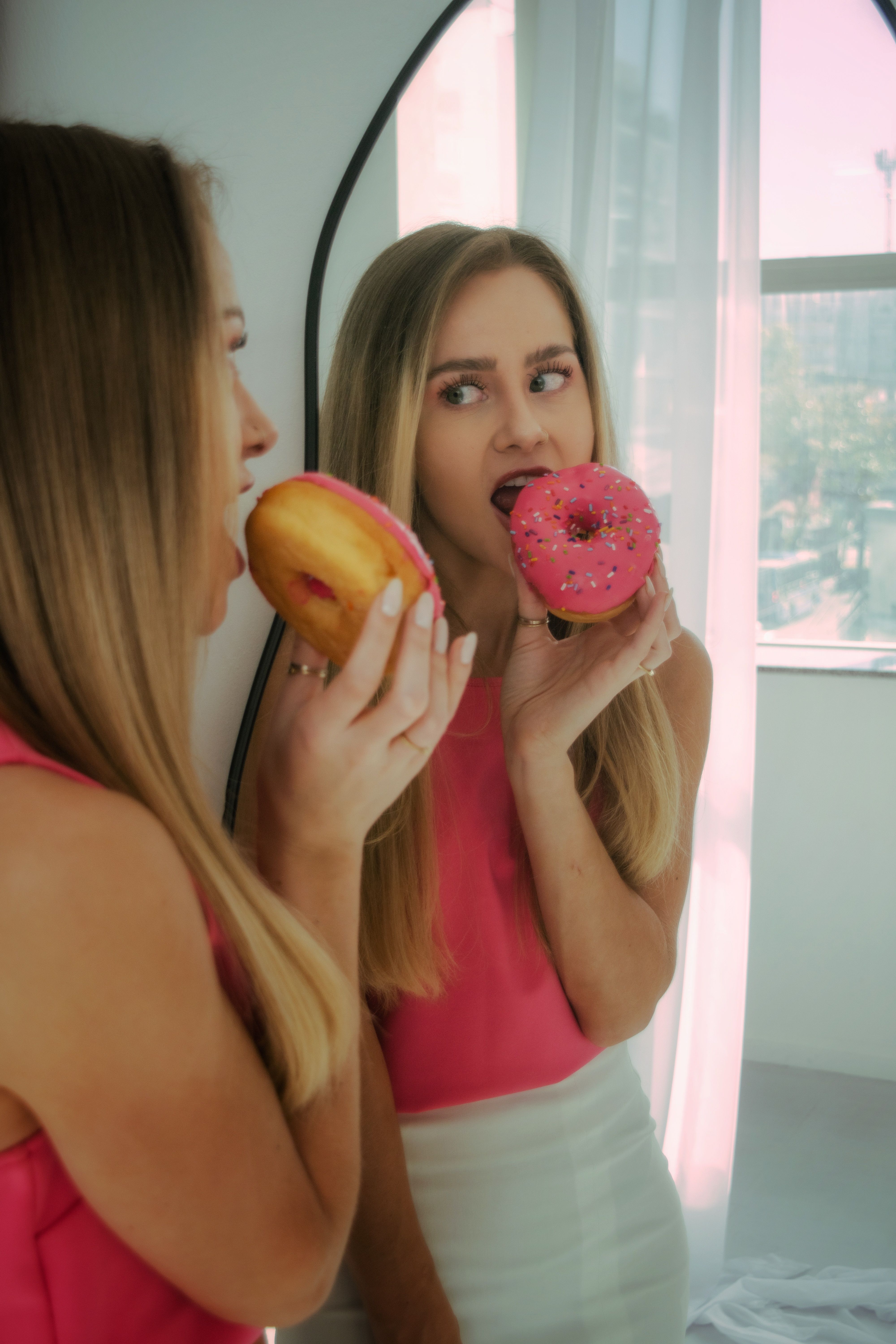 Woman Eating Donuts in Front of Mirror · Free Stock Photo