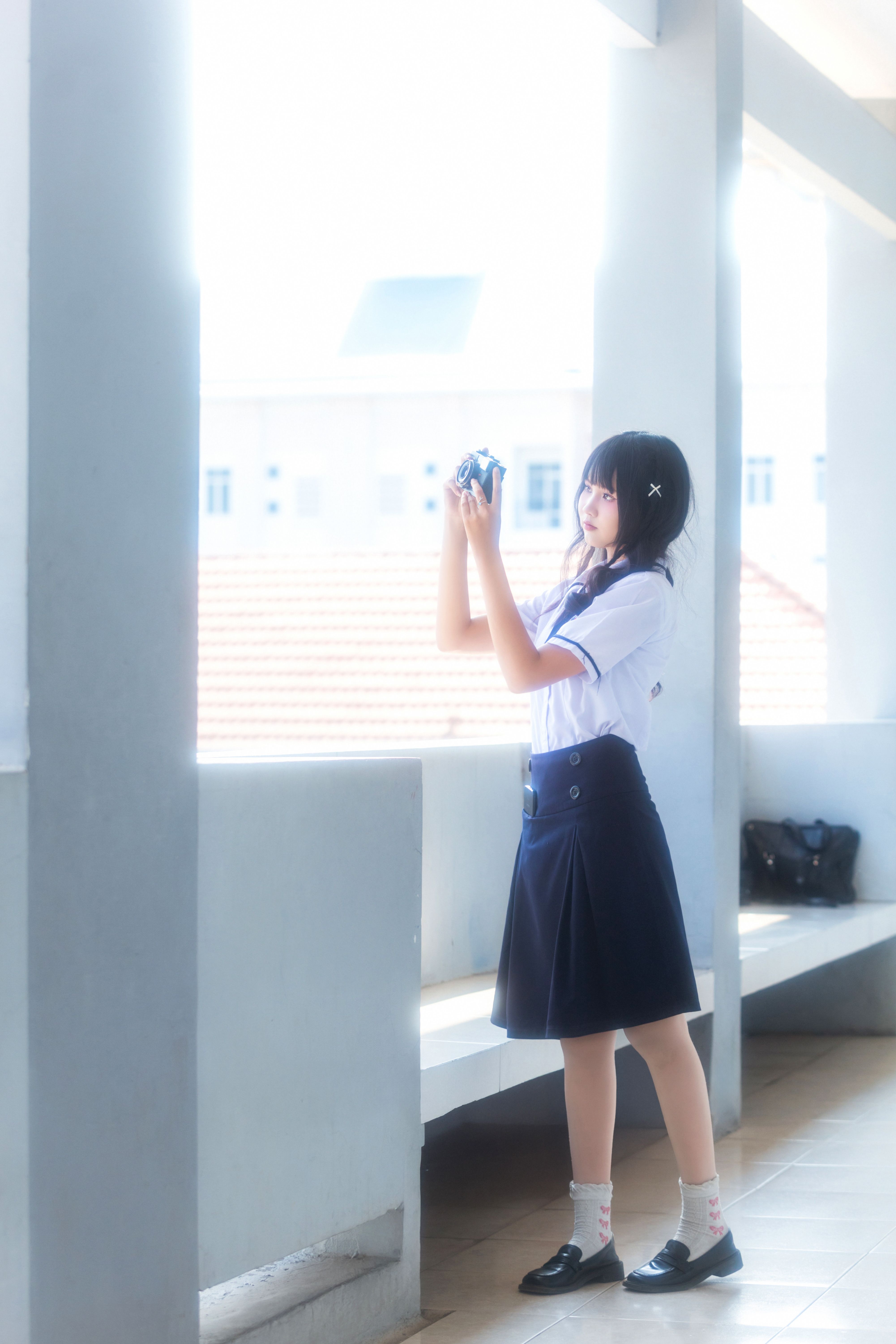 Student in Uniform Holding a Camera Indoors · Free Stock Photo