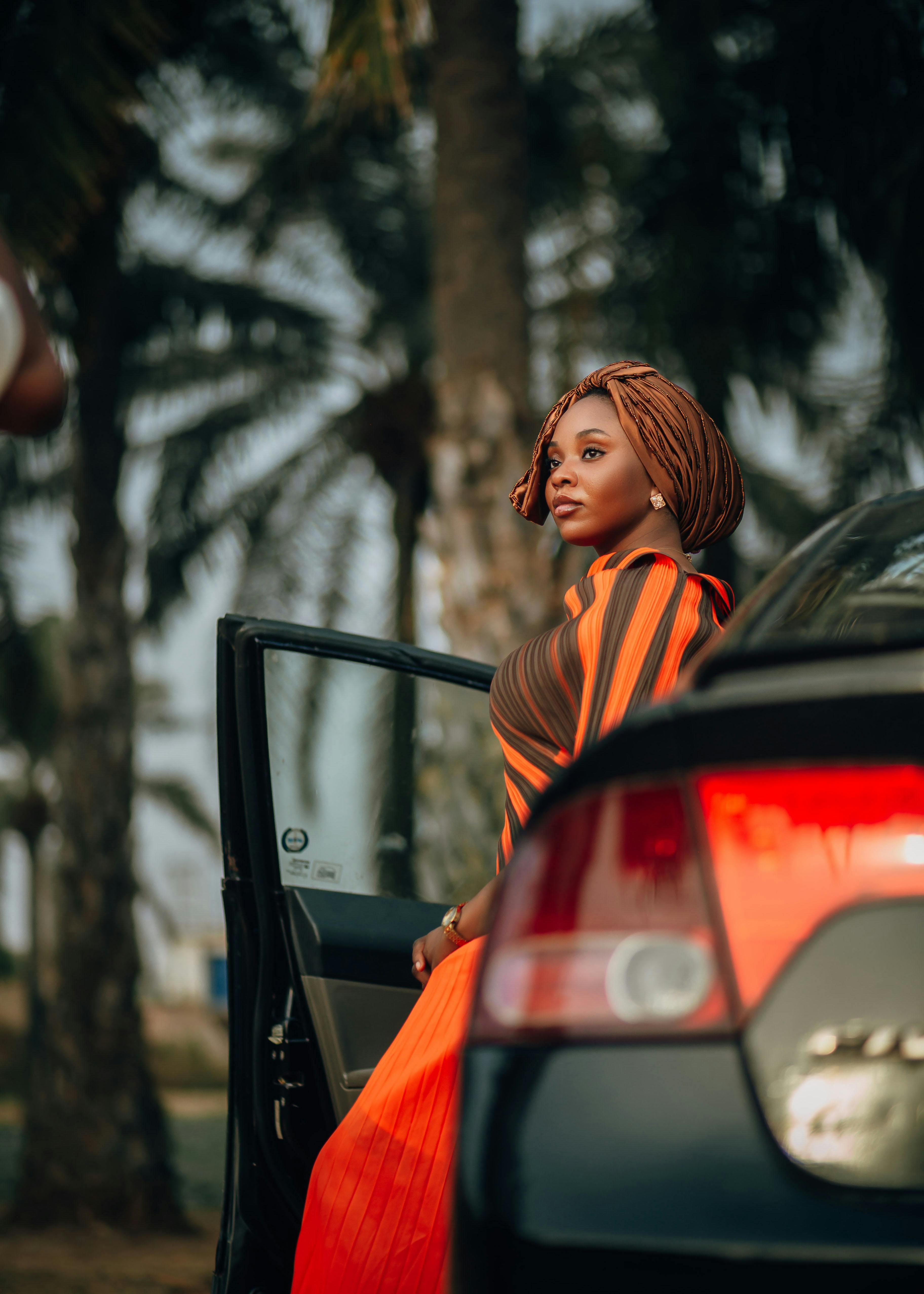 Woman in Orange Dress Exiting Car Outdoors · Free Stock Photo