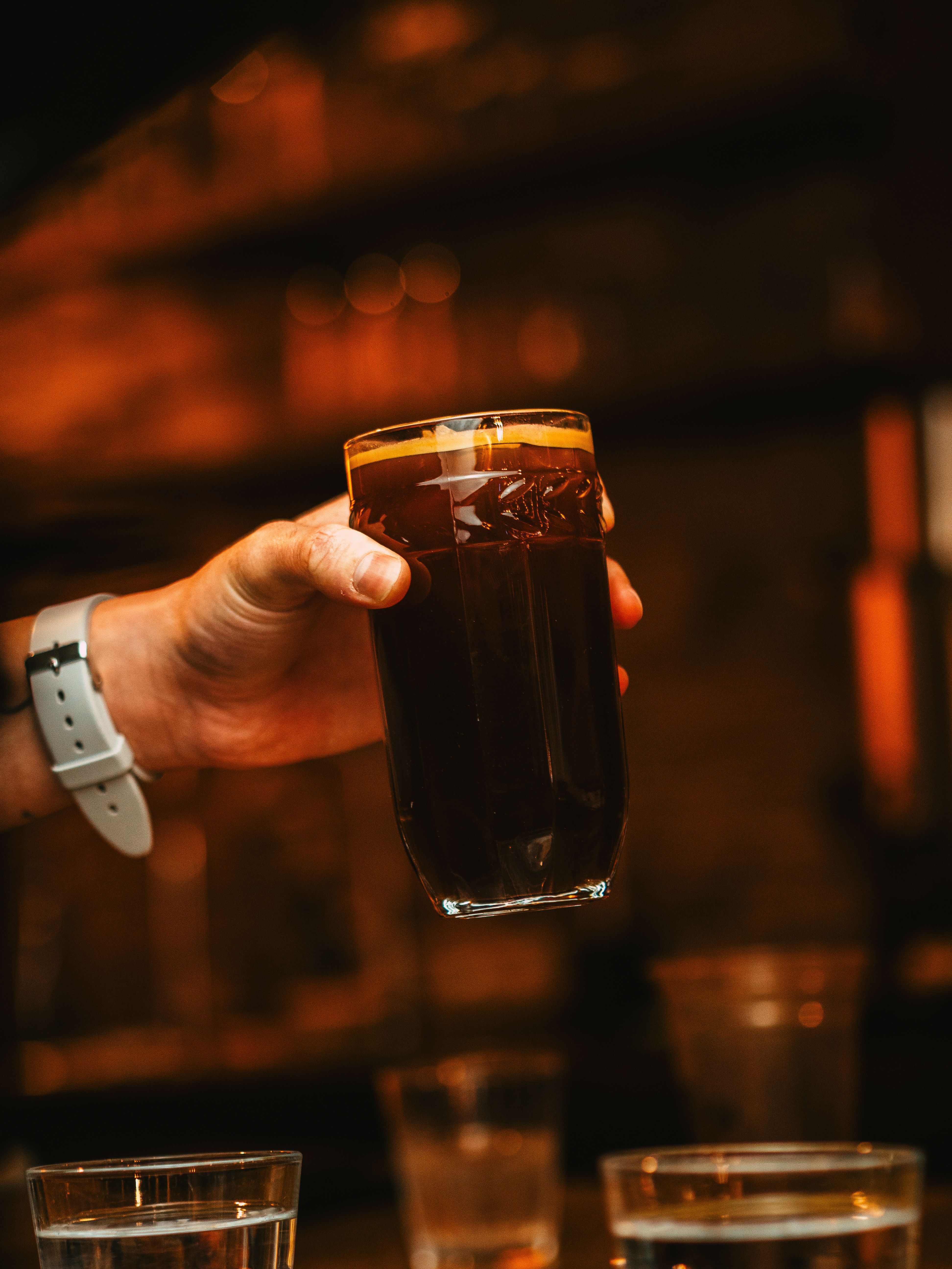 Hand Holding Iced Coffee with Warm Lighting · Free Stock Photo