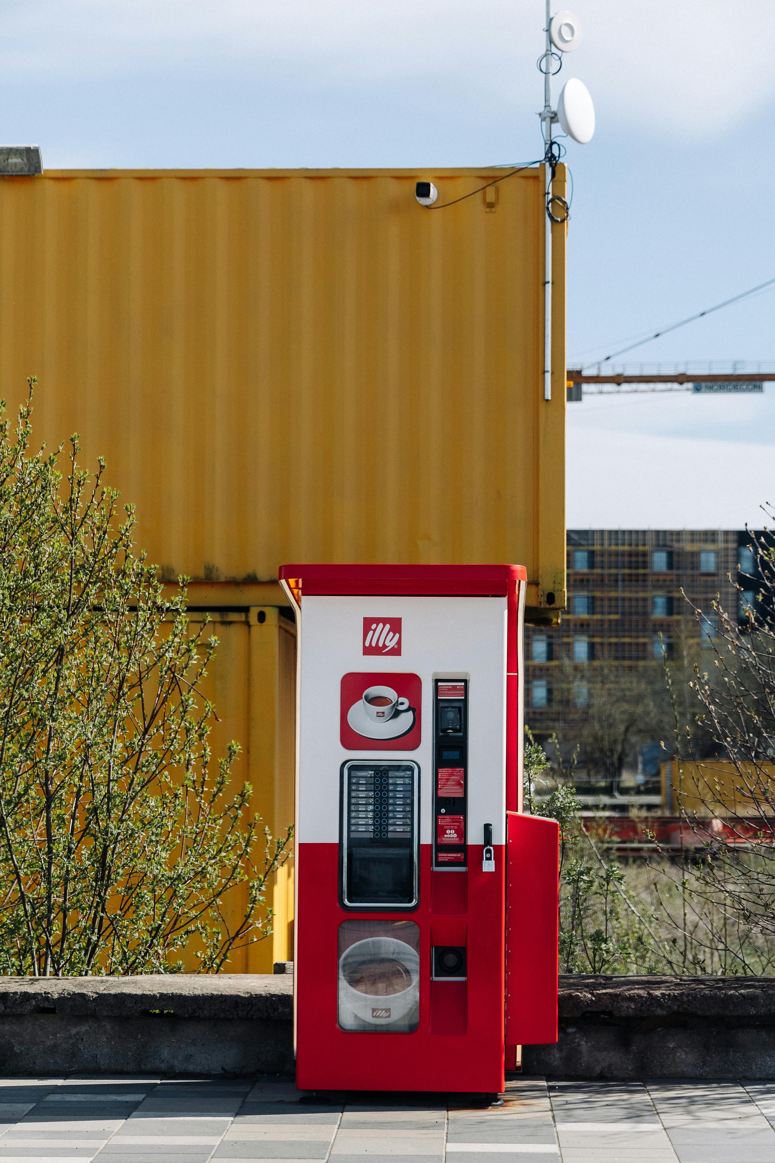 Coffee Vending Machine by Yellow Container Outdoors · Free Stock Photo