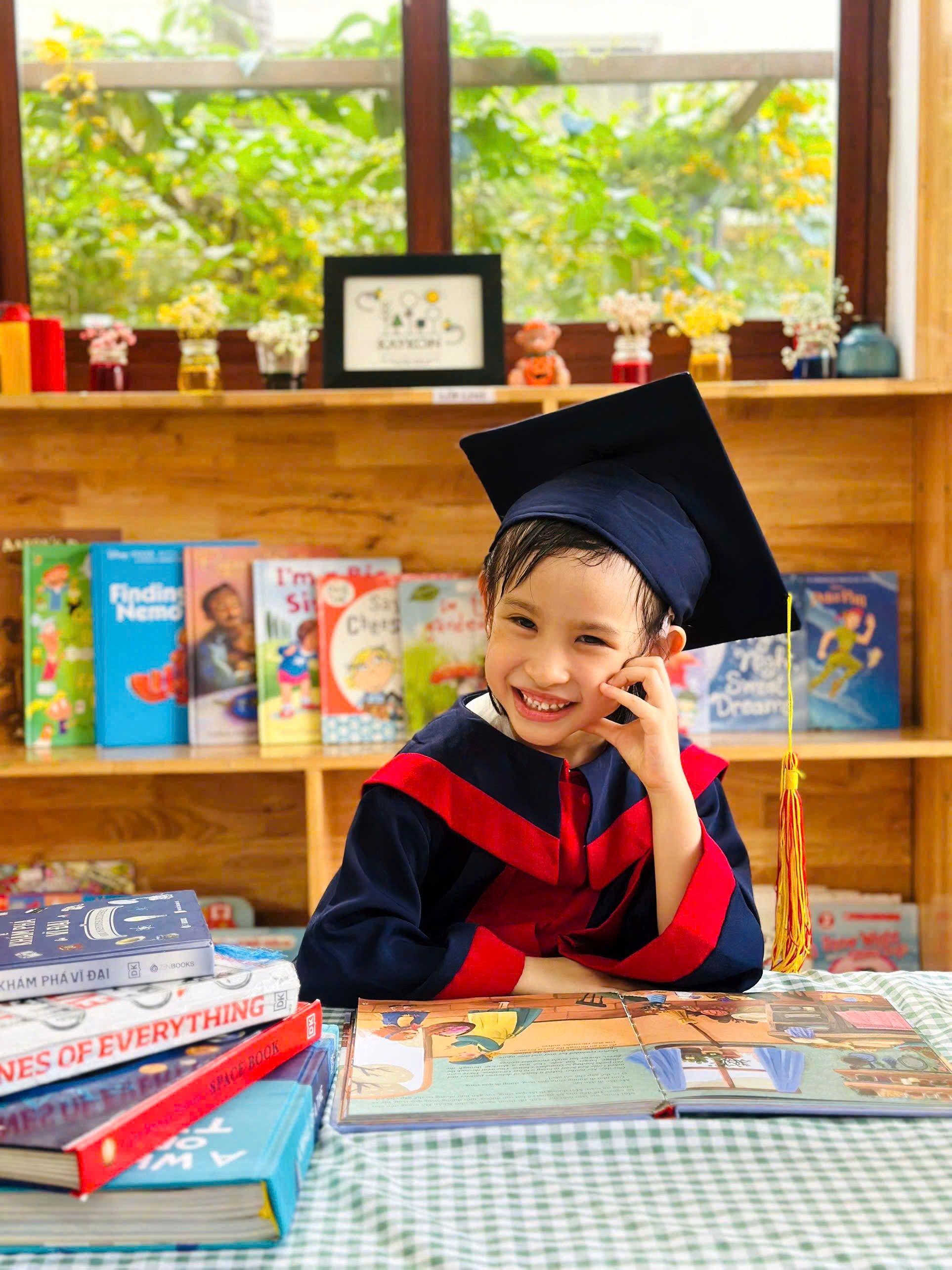 Young Child in Graduation Gown Smiling Indoors · Free Stock Photo