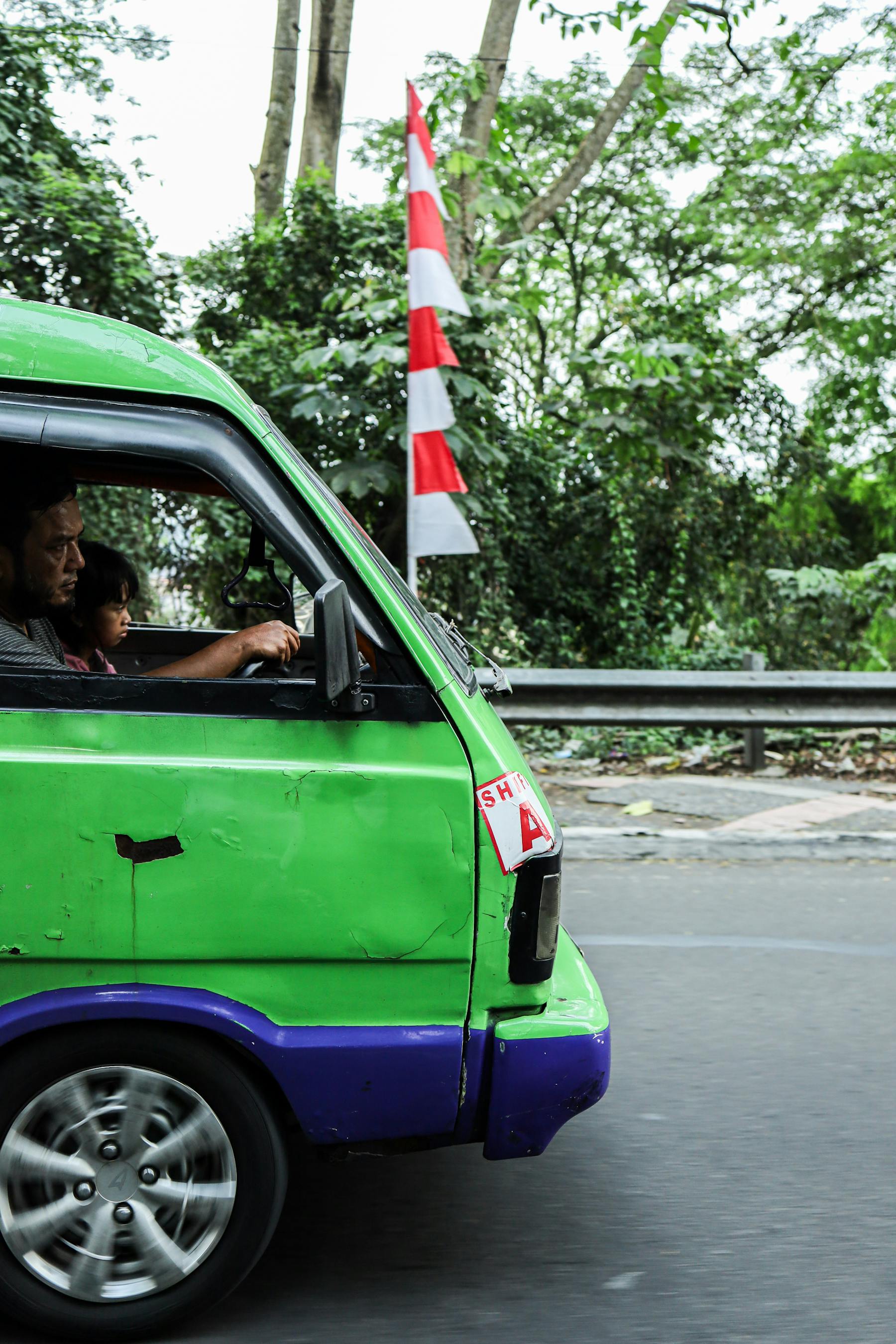 Green Minivan on Road with Driver and Passenger · Free Stock Photo