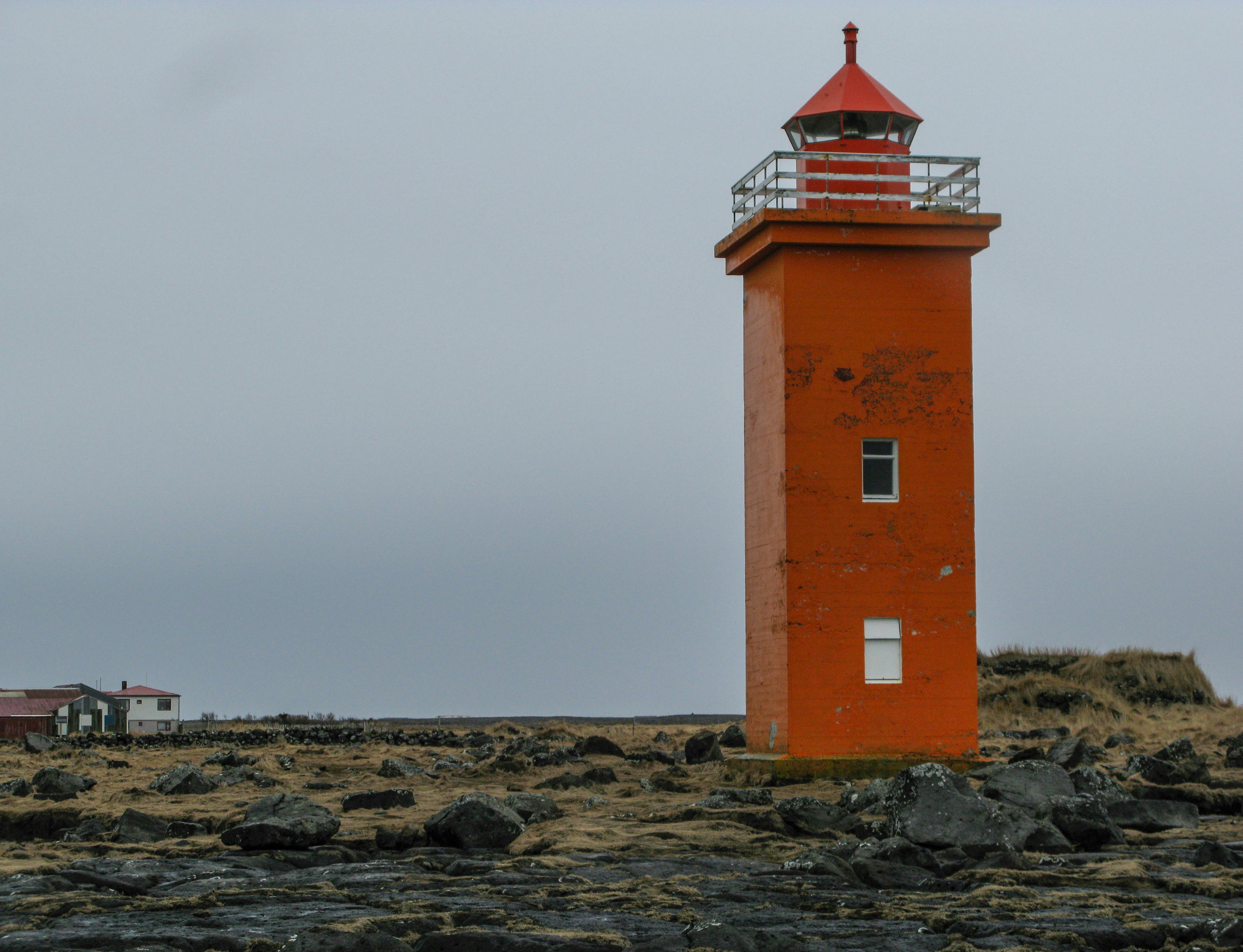 Bright Orange Lighthouse on Rocky Shoreline · Free Stock Photo