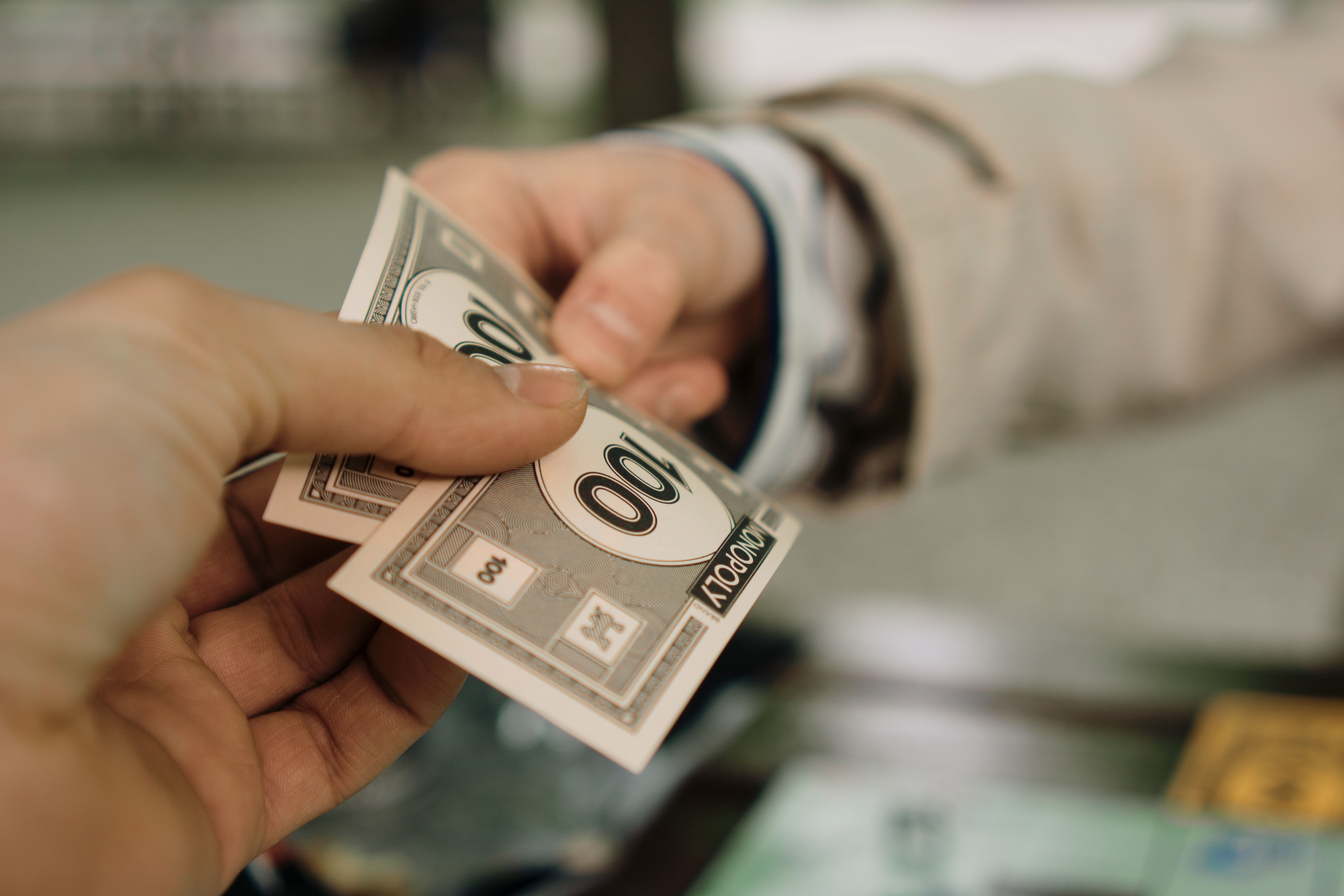 Free Close-up of two hands exchanging Monopoly money, symbolizing a ...