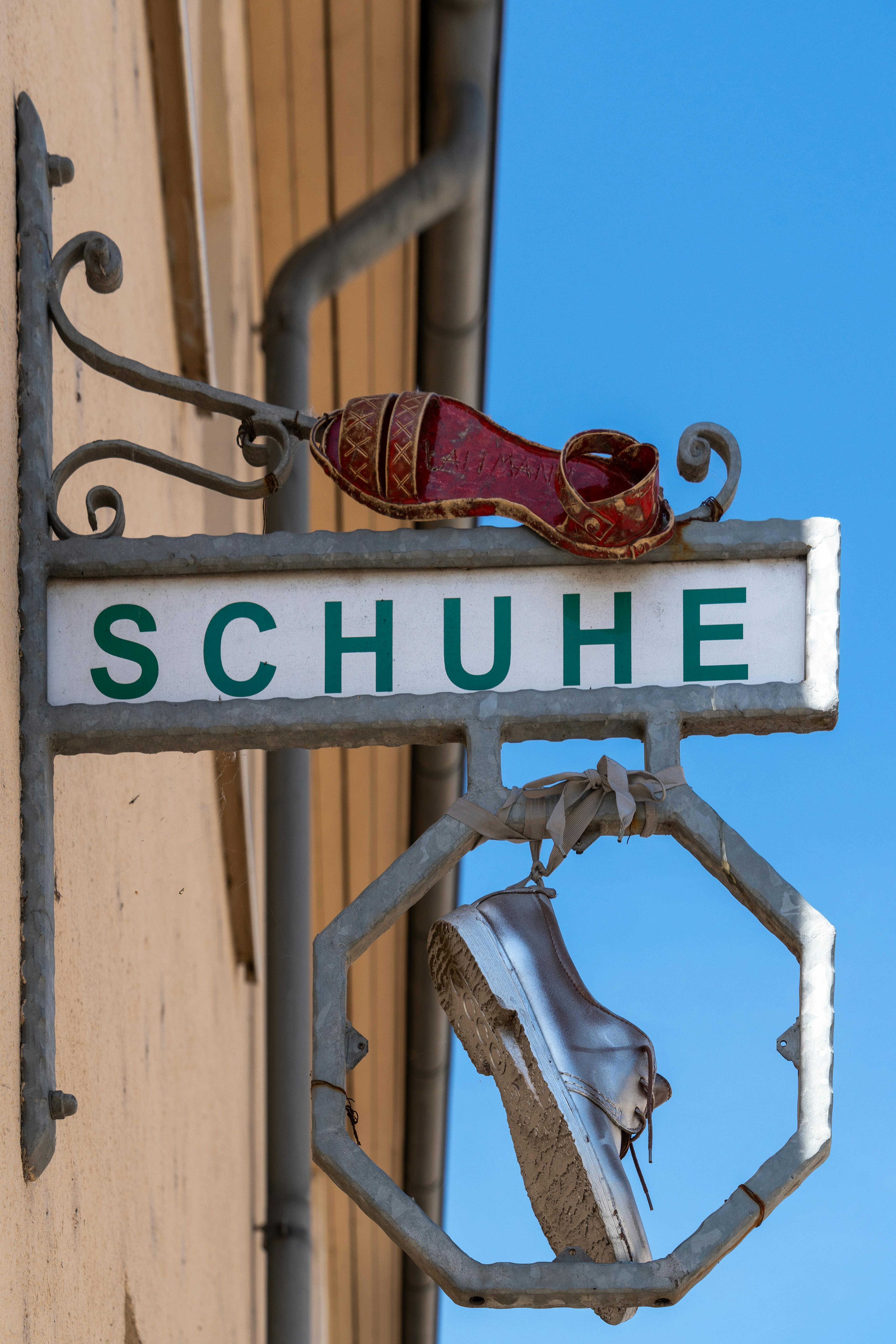 Vintage Shoe Store Sign with Hanging Footwear · Free Stock Photo