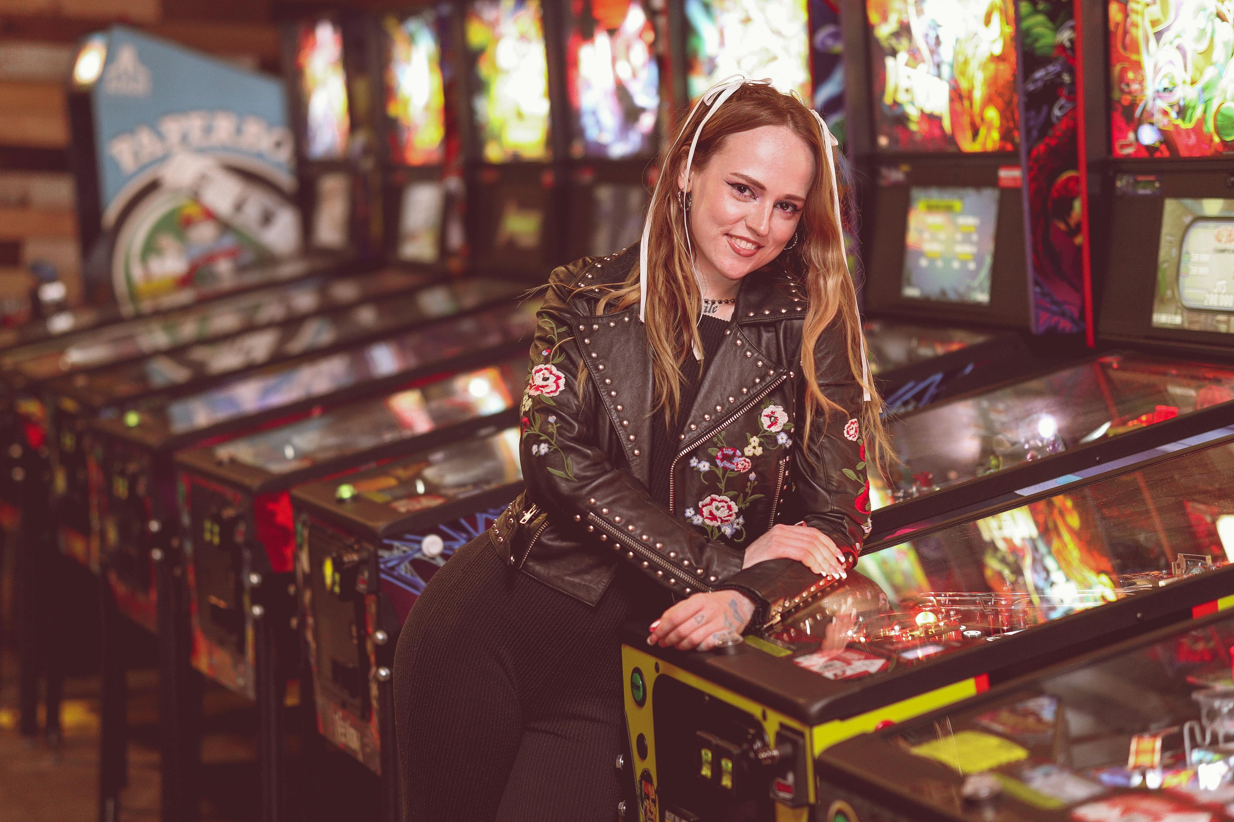 Smiling Woman at a Vintage Arcade Pinball Machine · Free Stock Photo