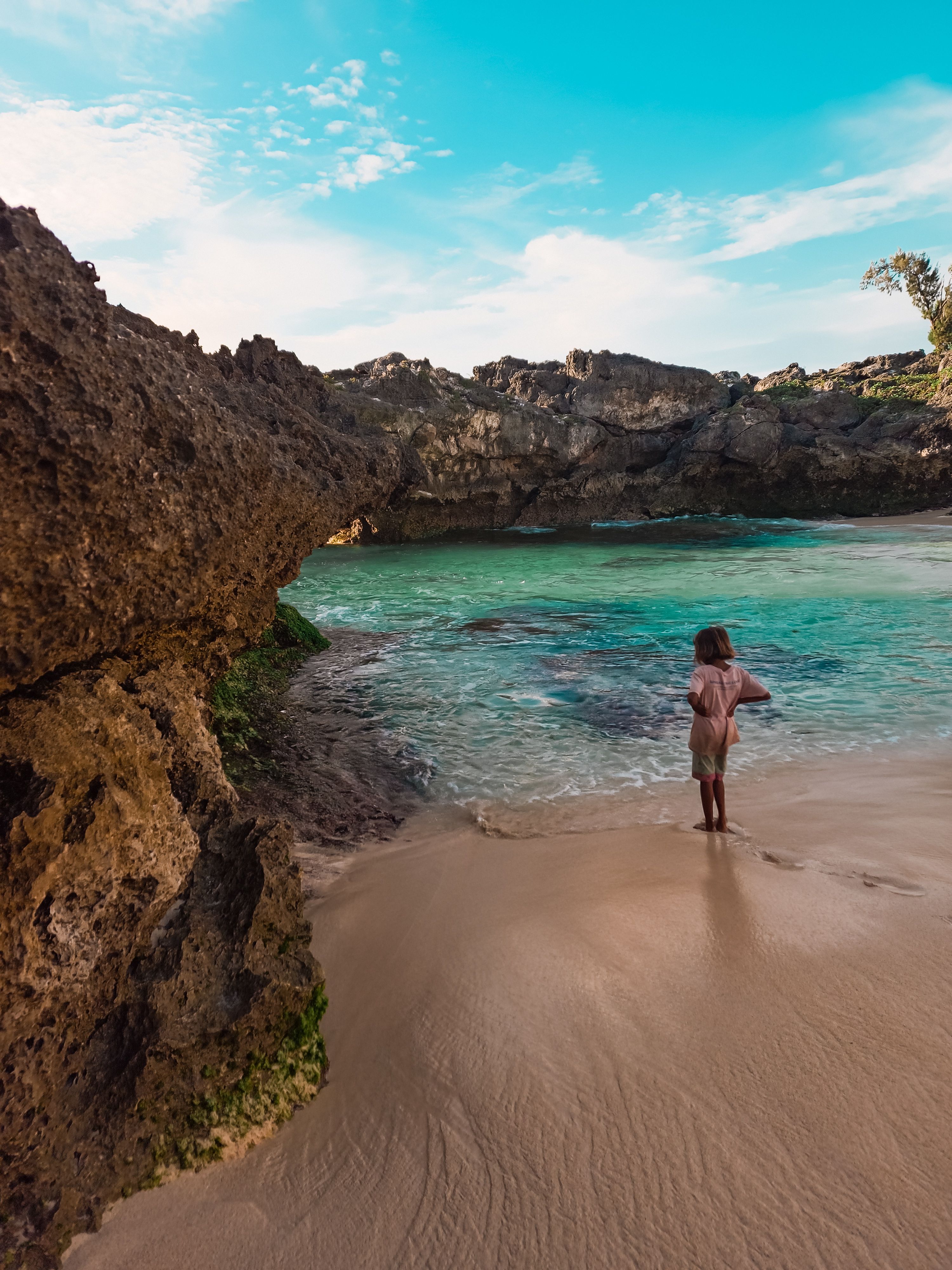 Child Exploring Scenic Beach with Rocky Cliff · Free Stock Photo