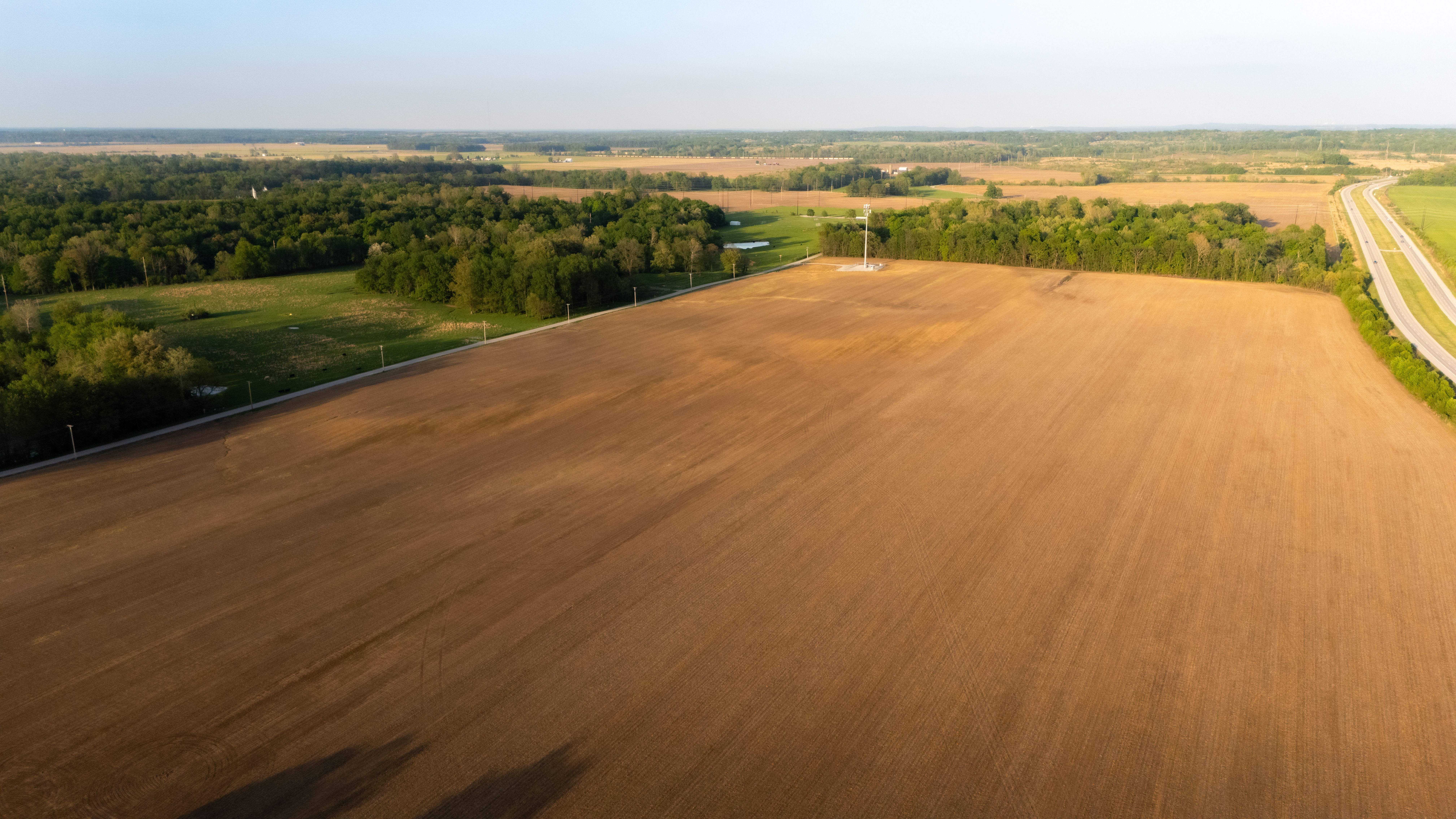 Aerial View of Expansive Crop Field and Forest · Free Stock Photo
