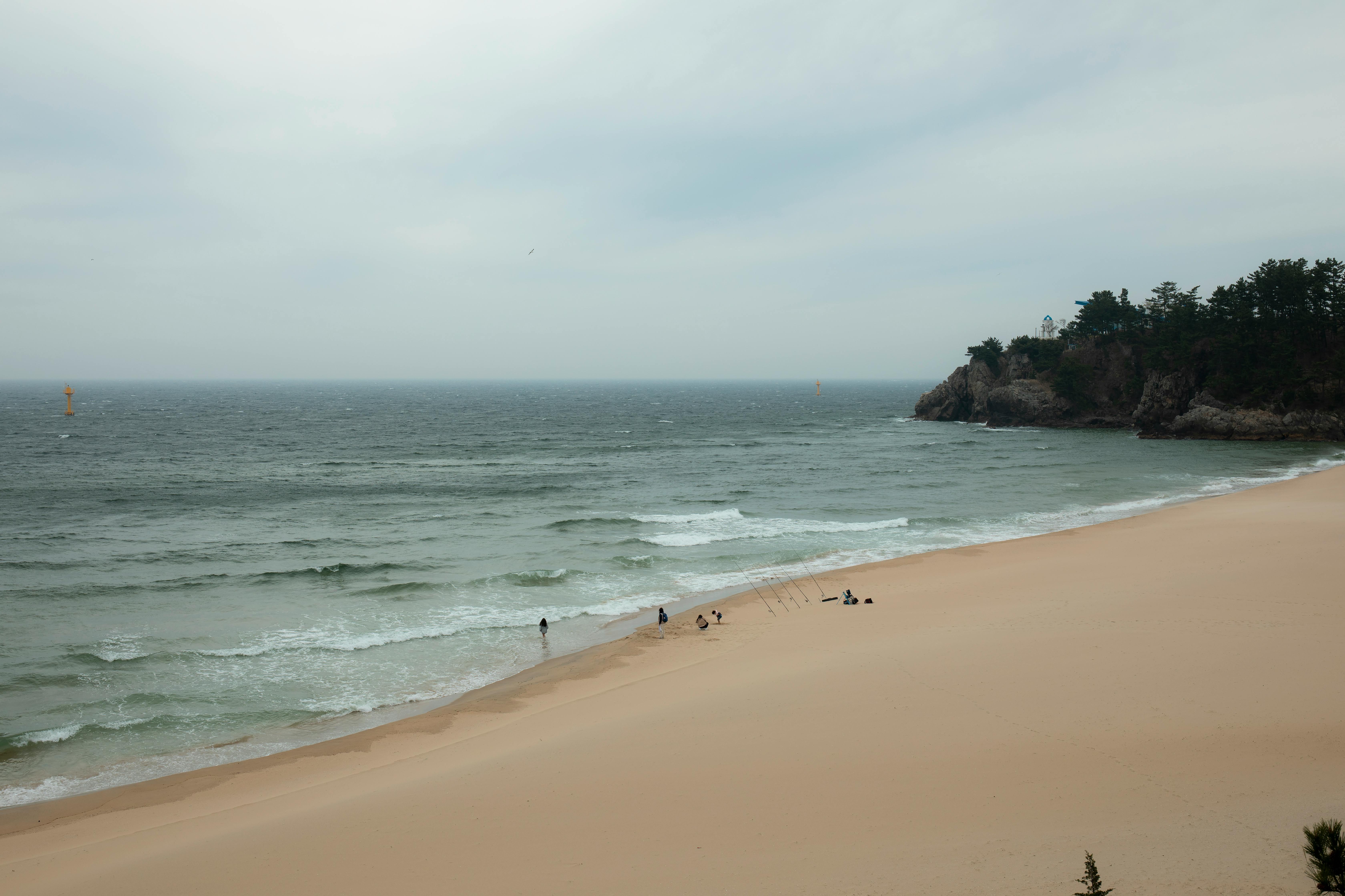 Tranquil Beach with Gentle Waves and Distant Cliff · Free Stock Photo