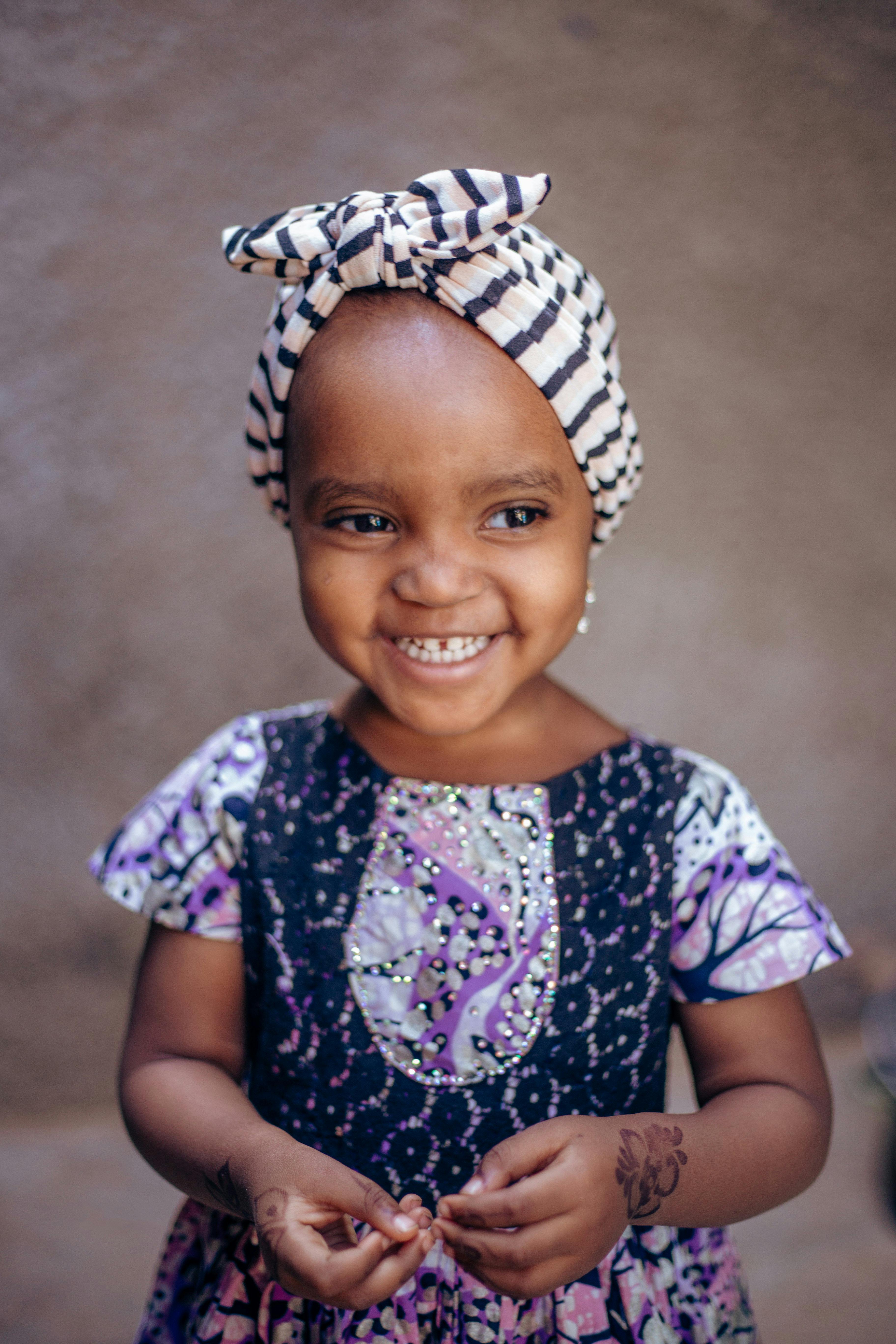 Smiling Child with Cloth on Head Outdoors · Free Stock Photo