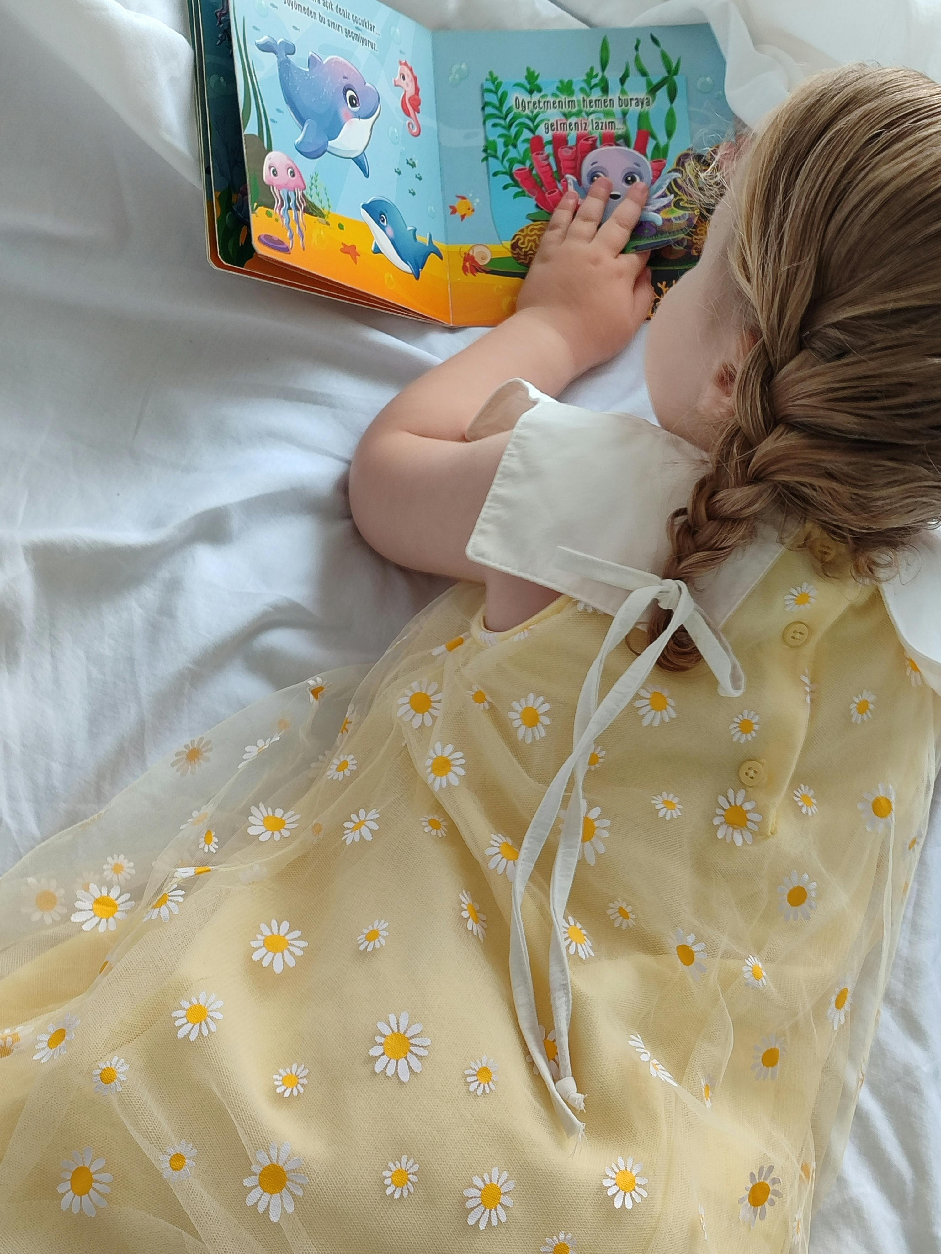 Child Reading Colorful Storybook on Bed · Free Stock Photo