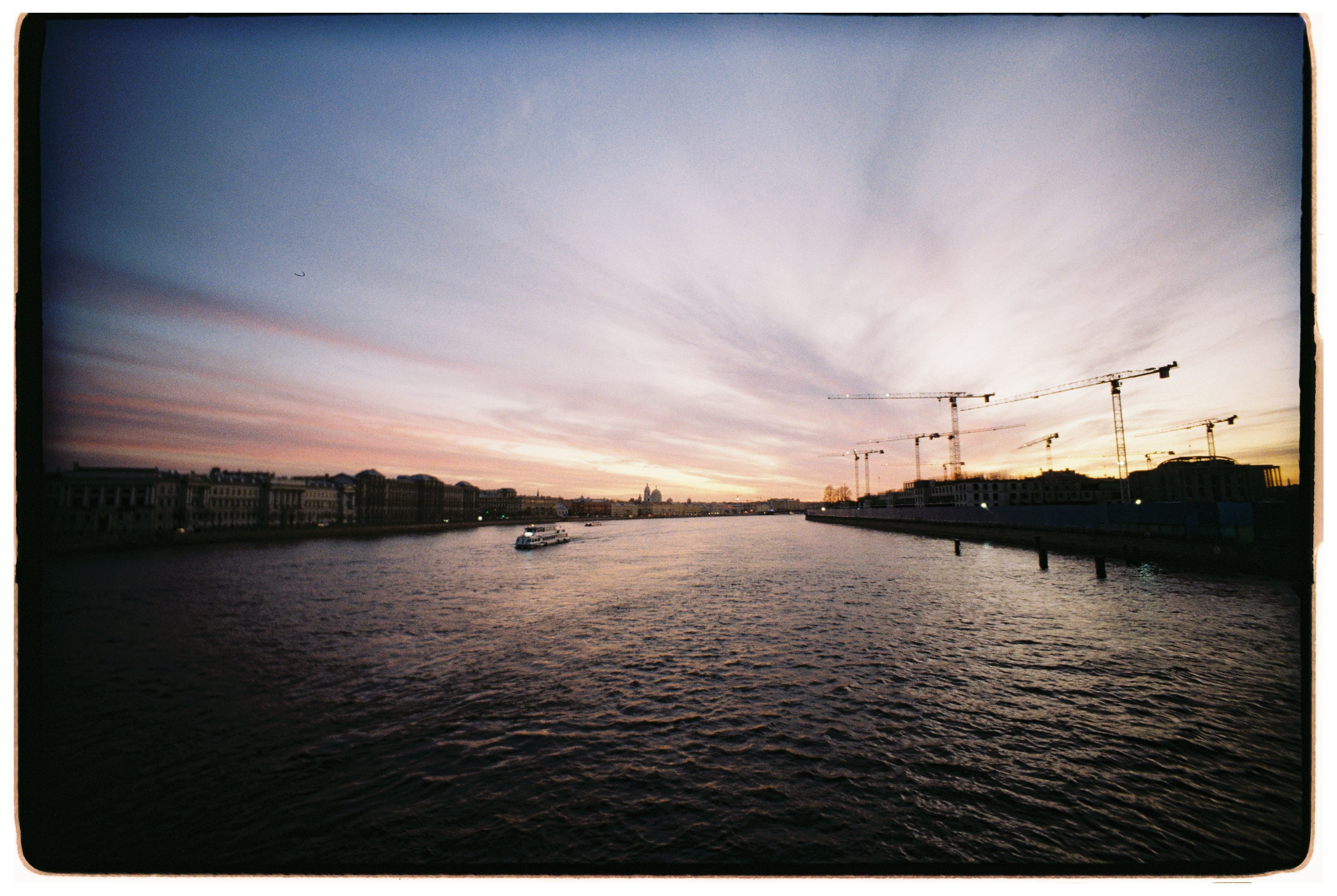 Sunset Over River with Cityscape and Cranes · Free Stock Photo