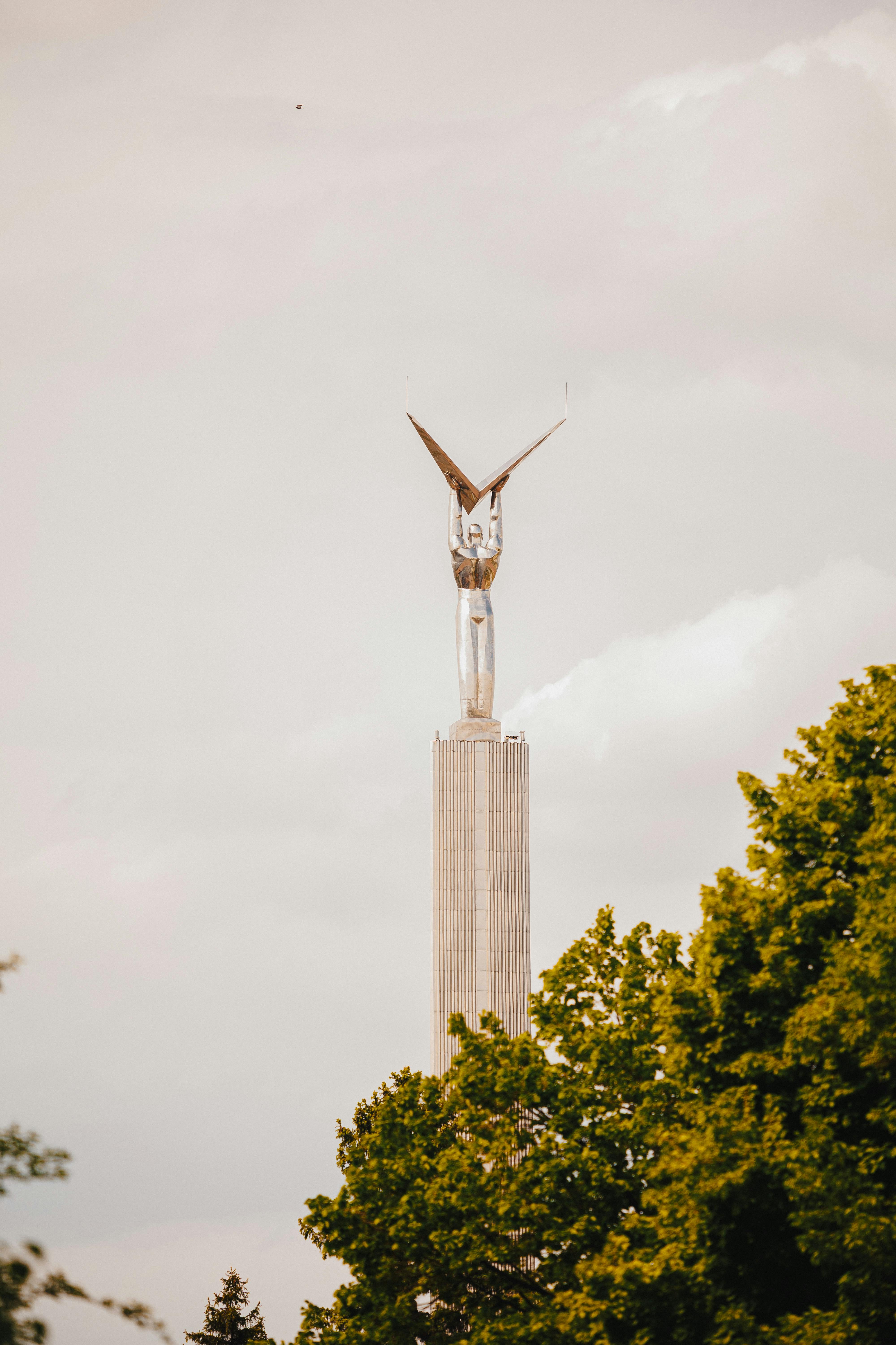 Tall Monument with Angelic Statue Under Cloudy Sky · Free Stock Photo