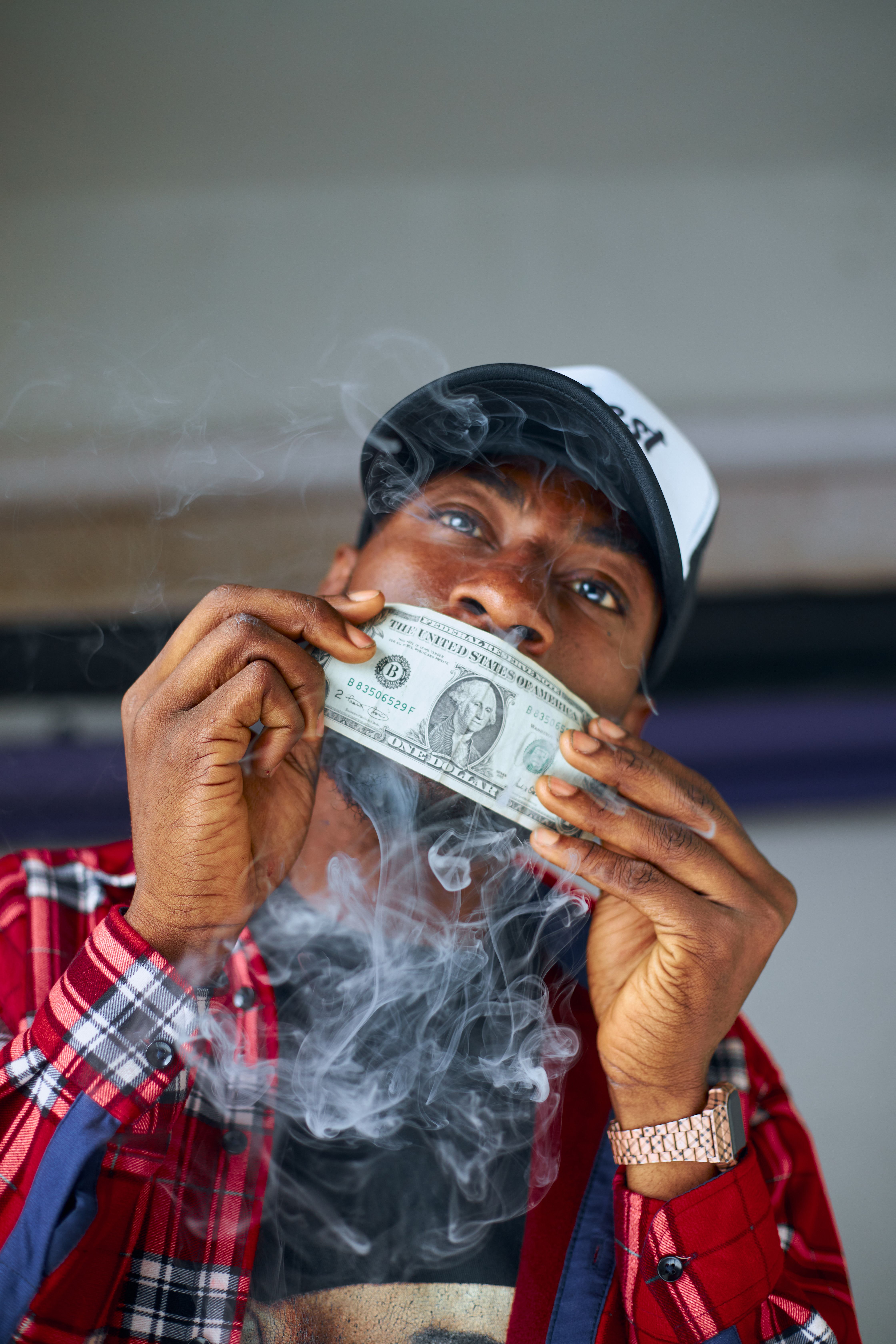 Man Holding Dollar Bill Surrounded by Smoke · Free Stock Photo