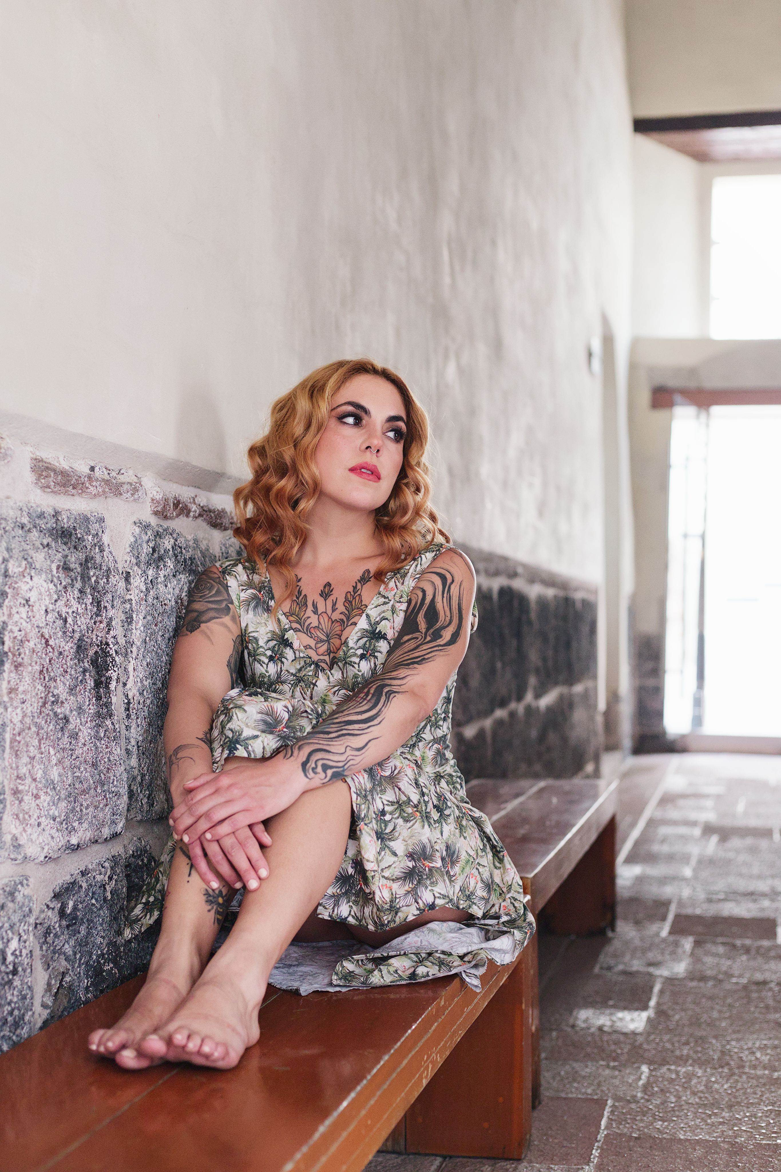Contemplative Woman With Tattoos Sitting Indoors · Free Stock Photo
