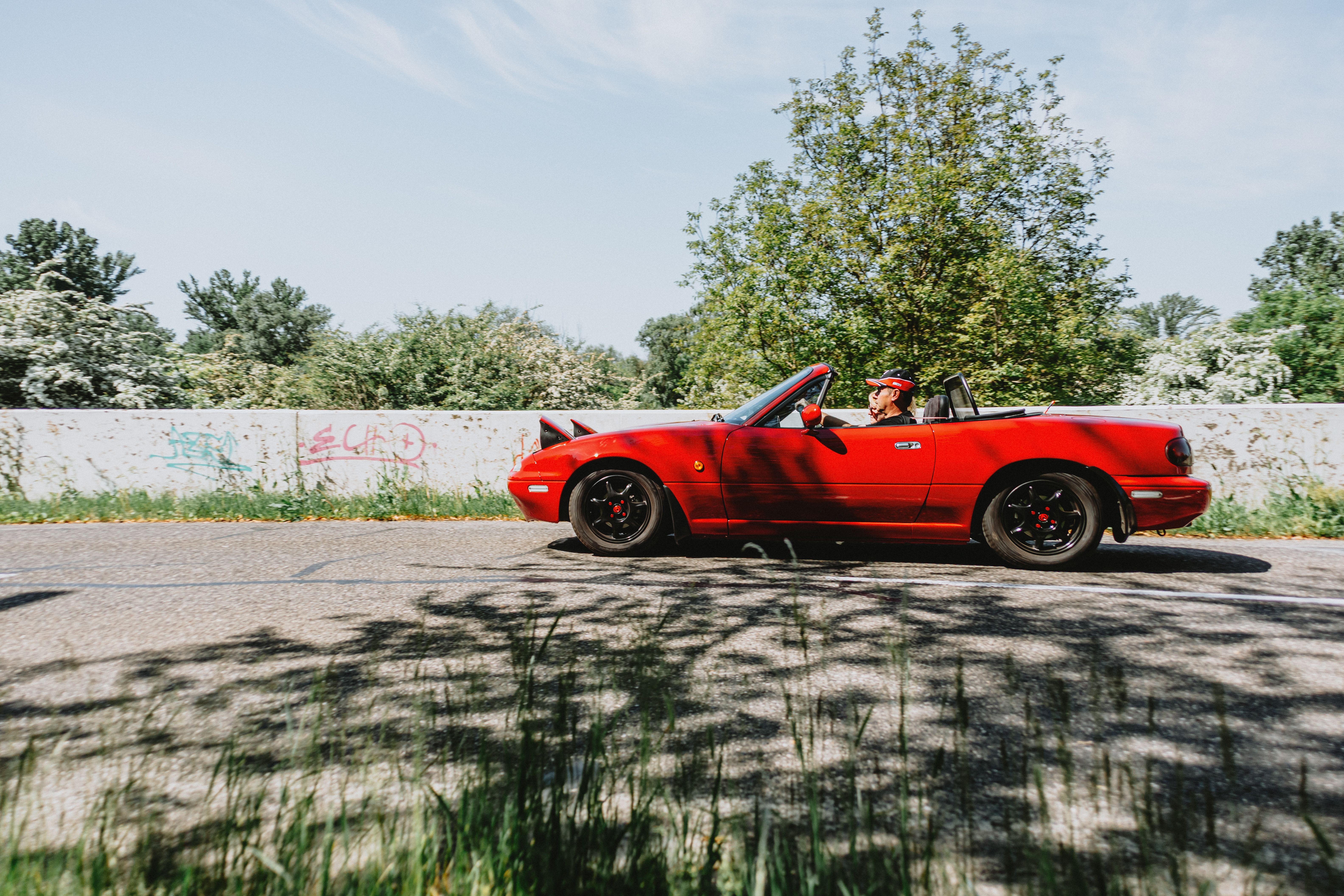 Sleek Red Convertible Driving on Sunny Day · Free Stock Photo