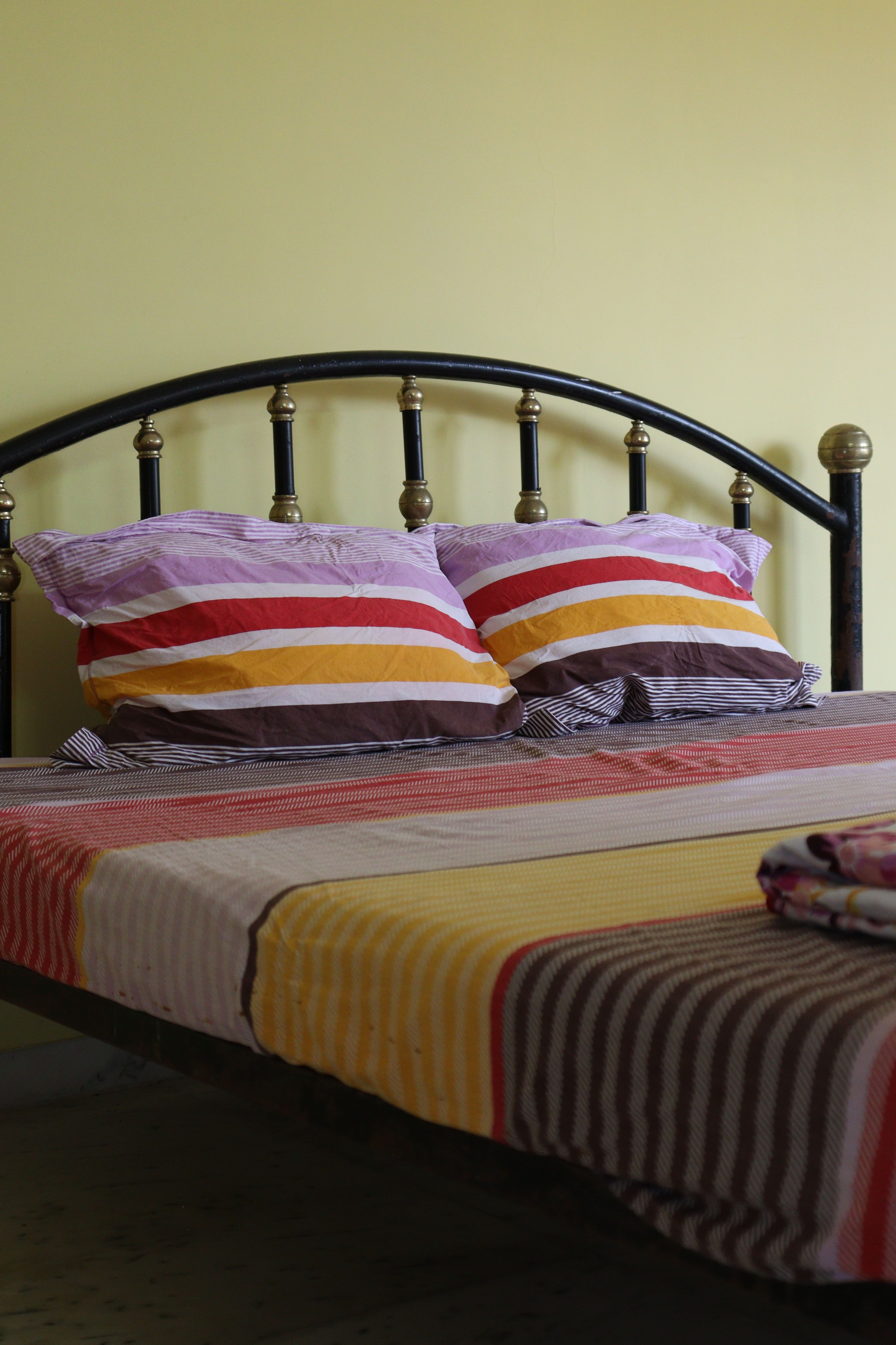 Colorful Striped Bedding on Black Steel Bedframe · Free Stock Photo