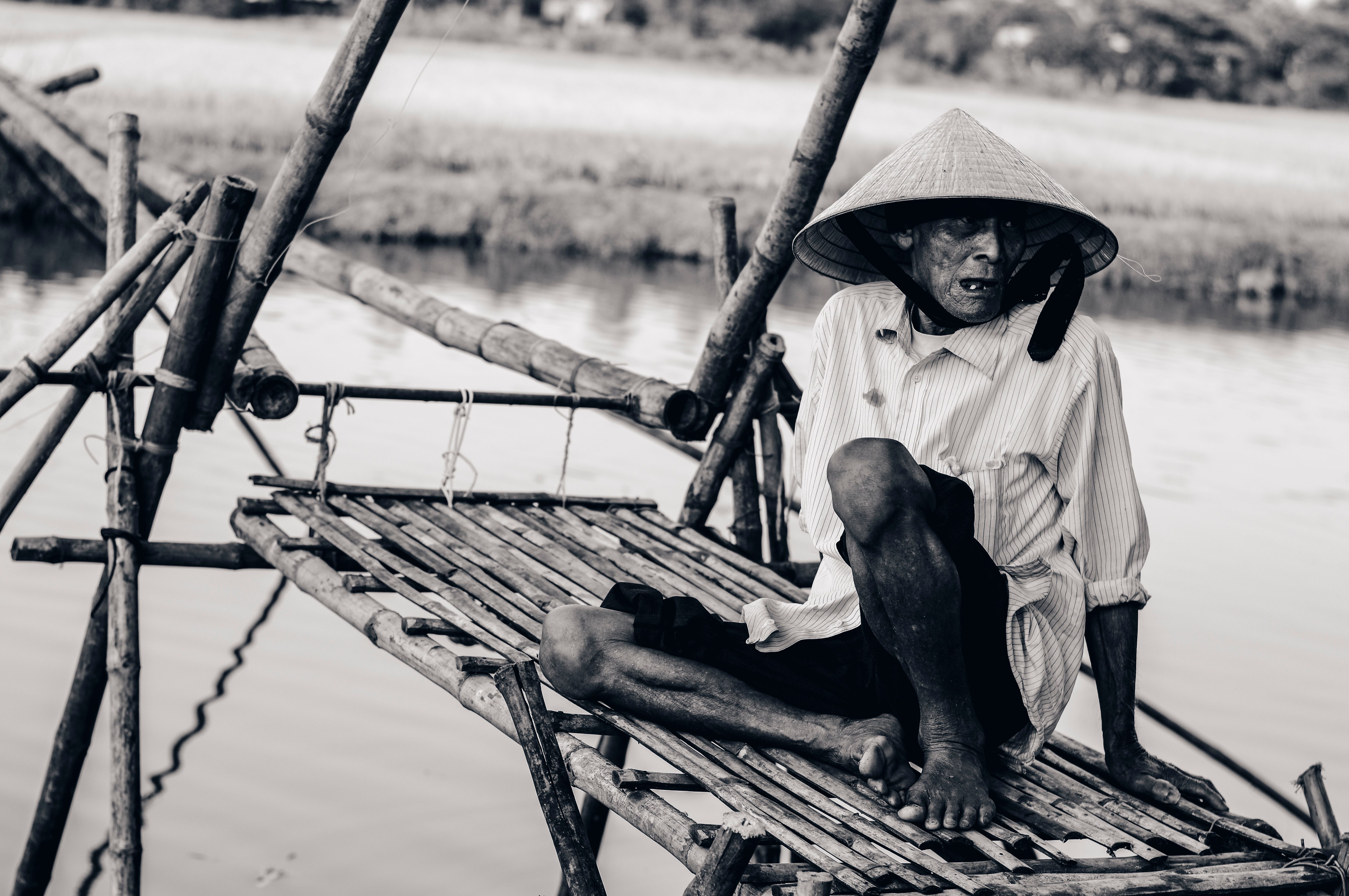 Elderly Man on Bamboo Raft by Riverbank · Free Stock Photo