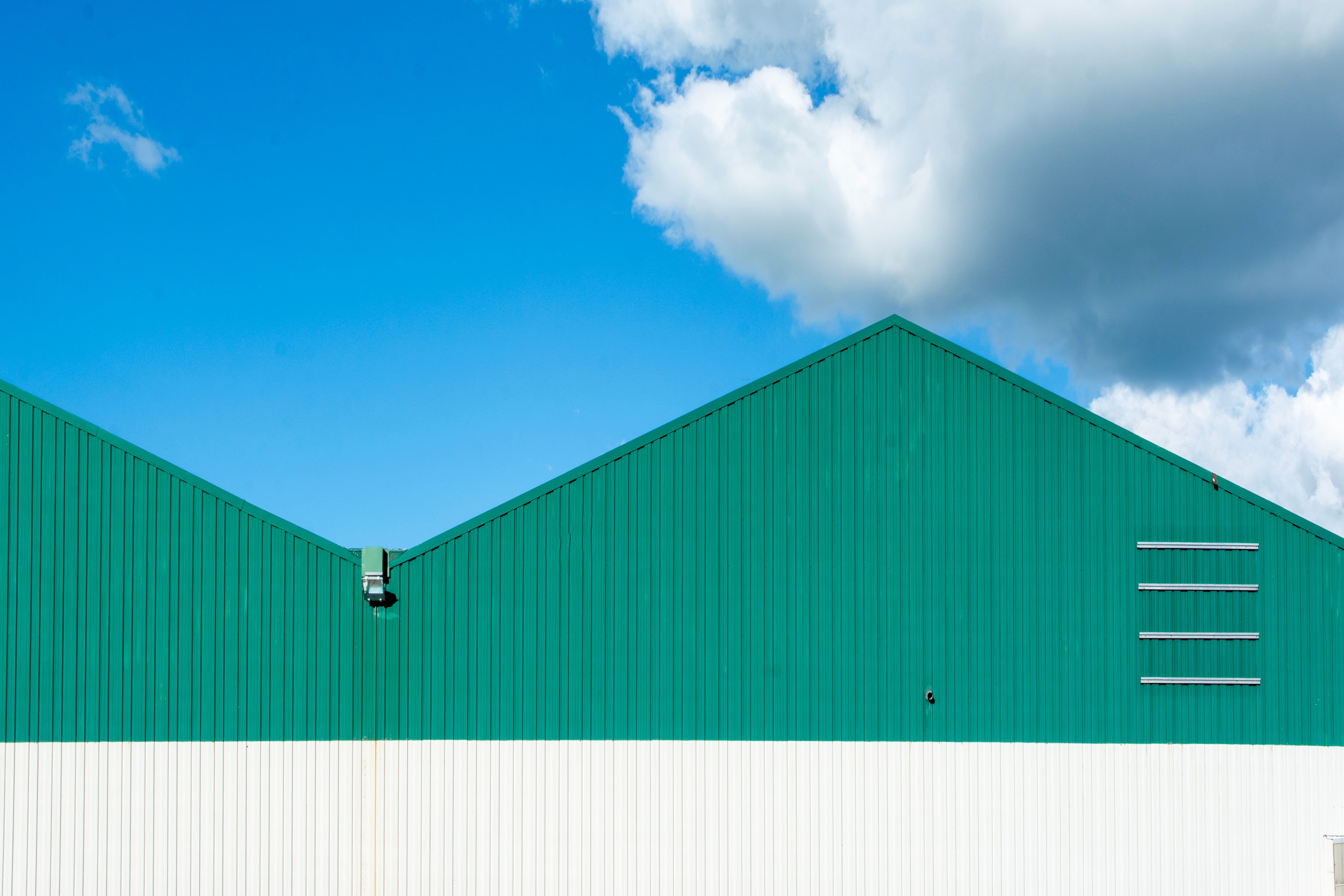 Green Industrial Warehouse Against Blue Sky · Free Stock Photo