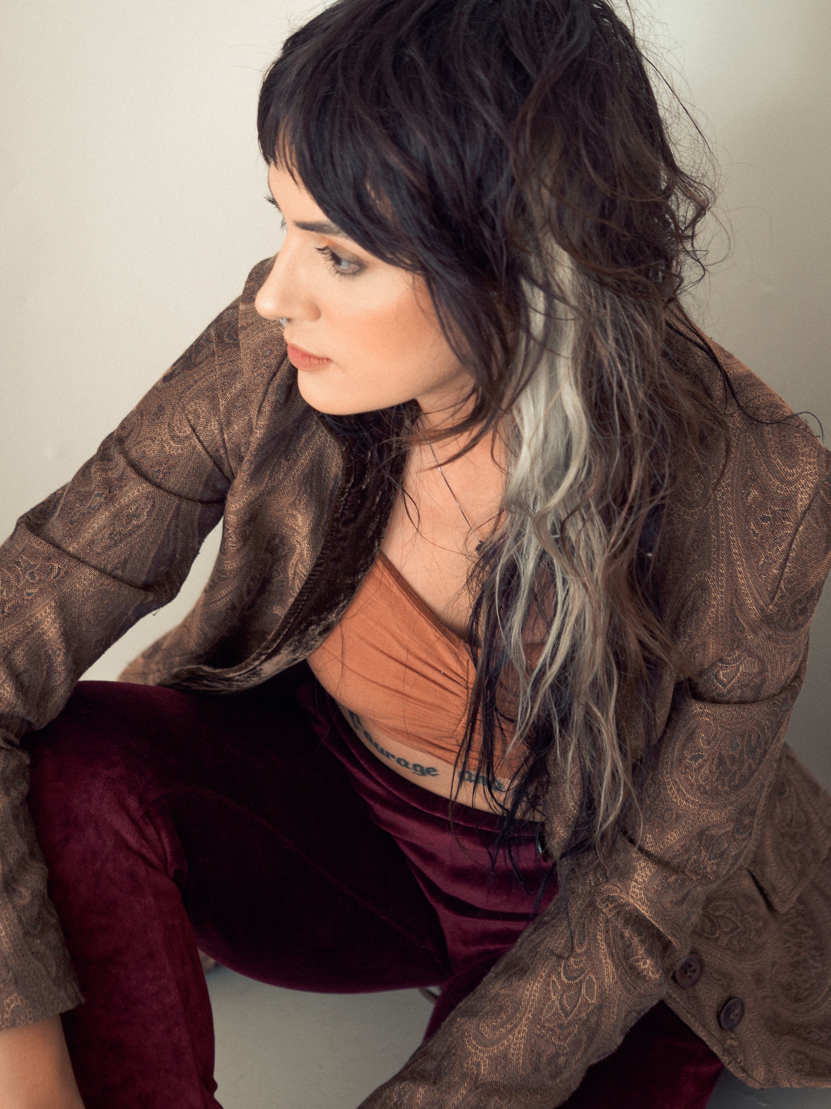 Stylish Woman in Boho Chic Attire Seated Indoors · Free Stock Photo