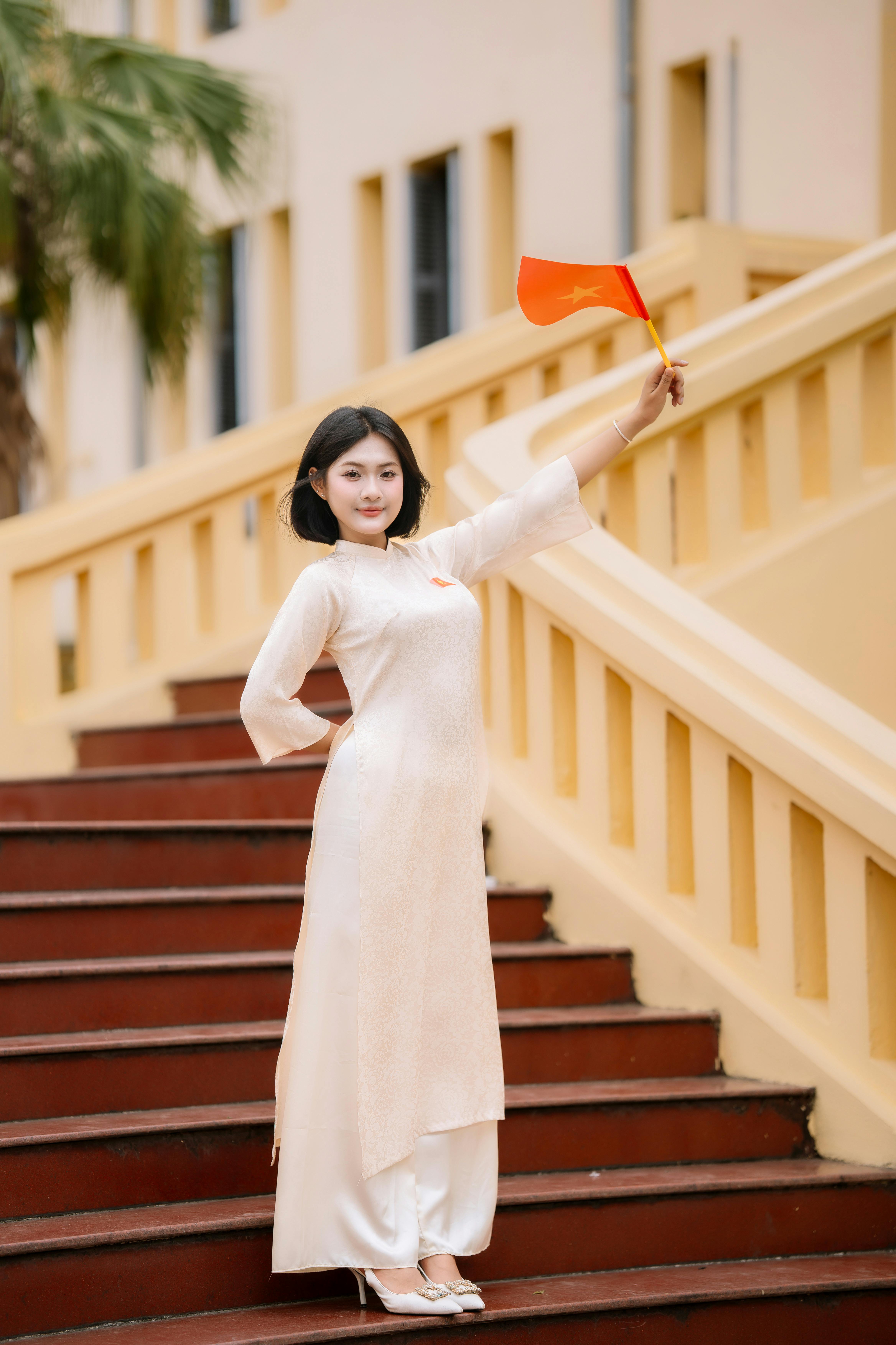 Elegant Woman in White Áo Dài Holding Flag · Free Stock Photo