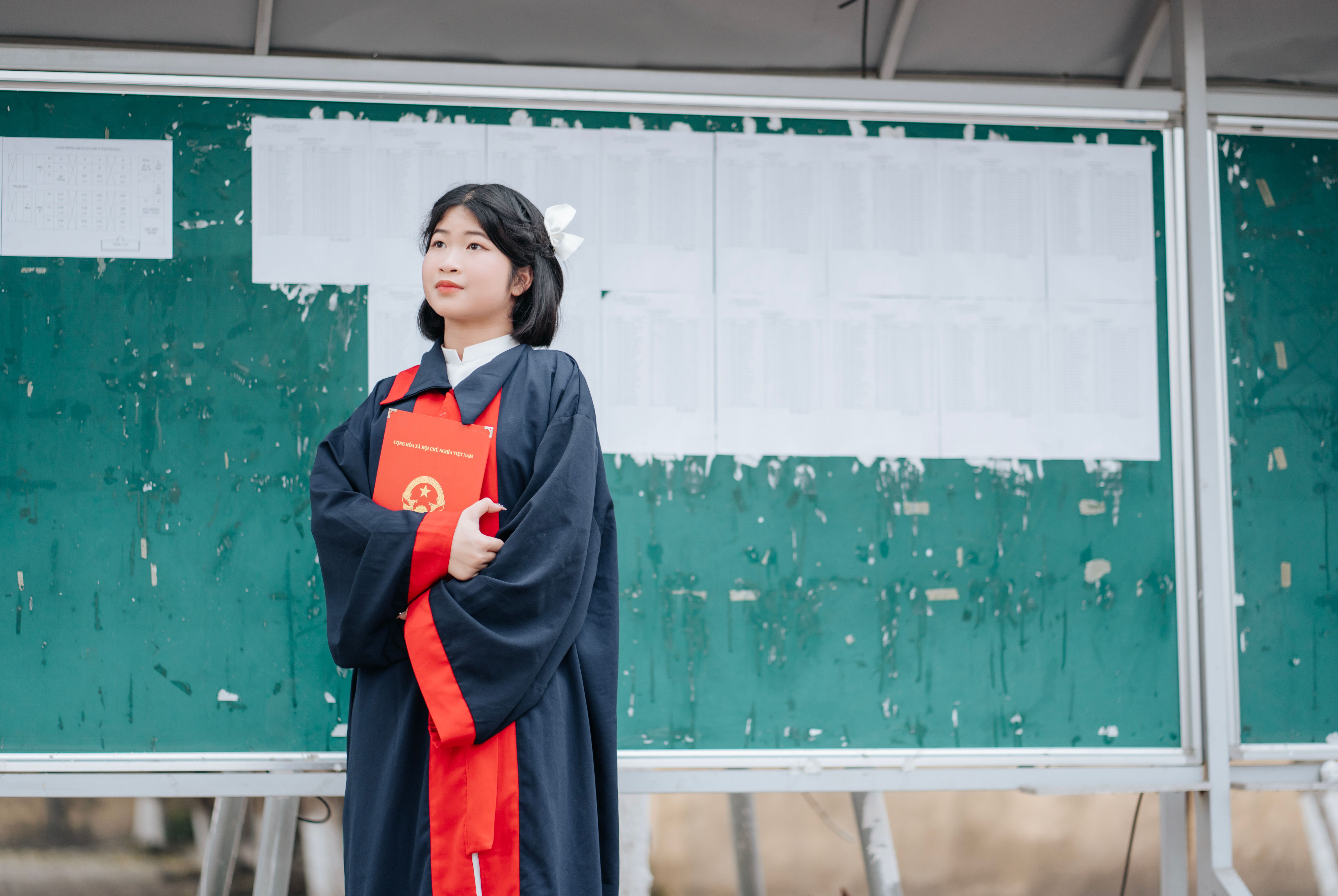 Young Graduate Posing with Diploma in Academic Gown · Free Stock Photo