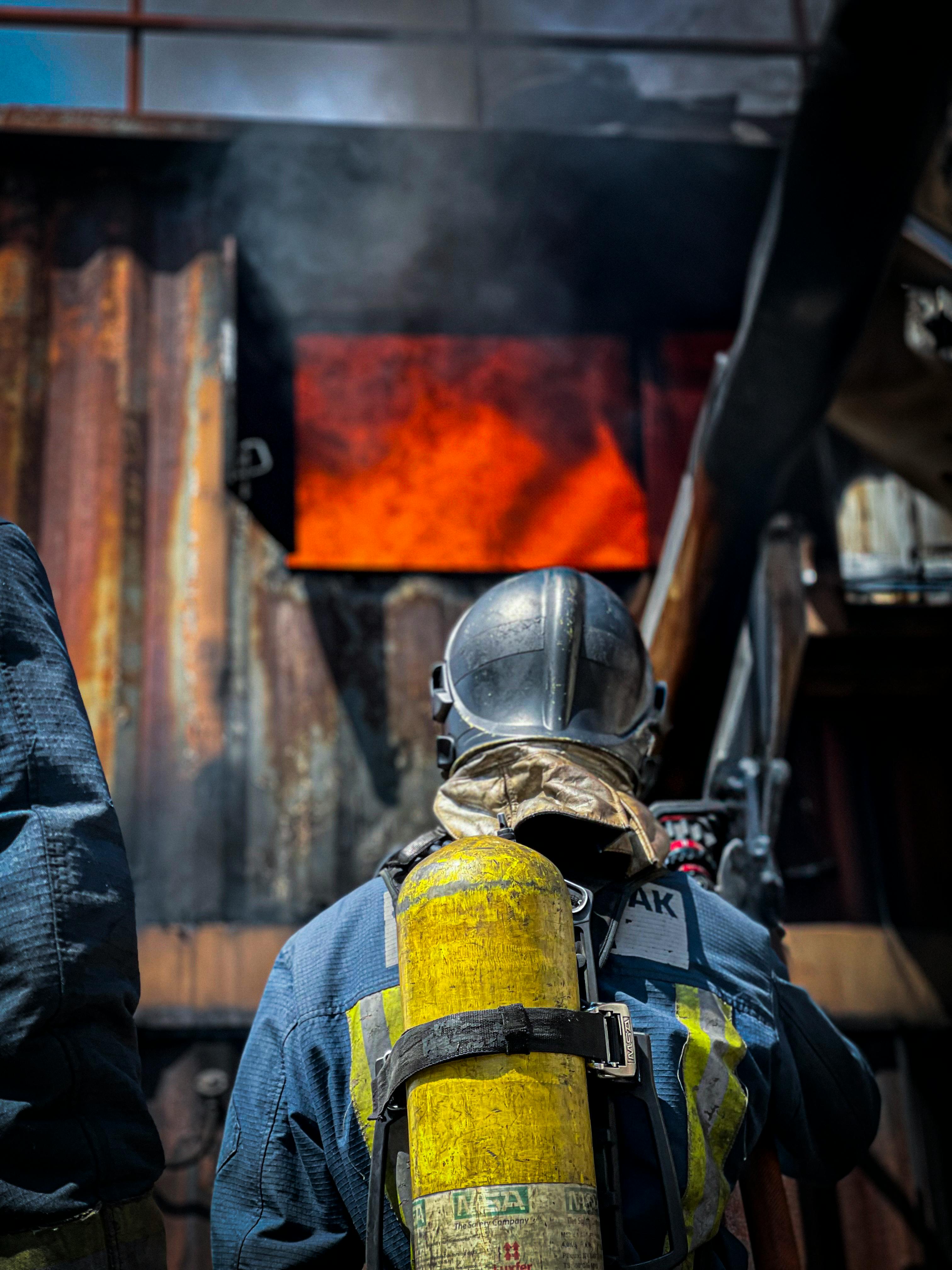 Firefighter Confronting Blazing Building in Action · Free Stock Photo