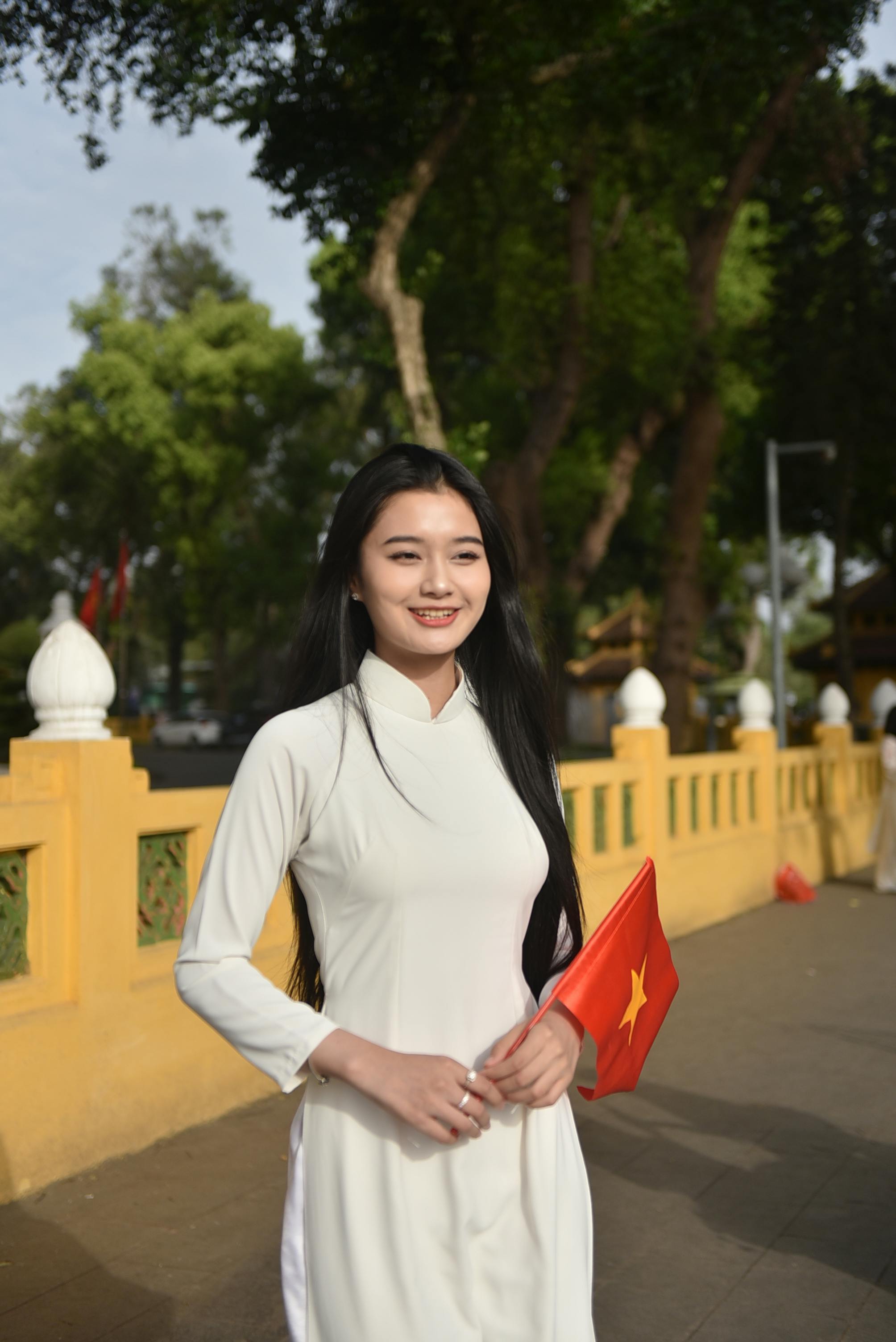 Young Woman in Traditional Áo Dài Holding Flag Outdoors · Free Stock Photo